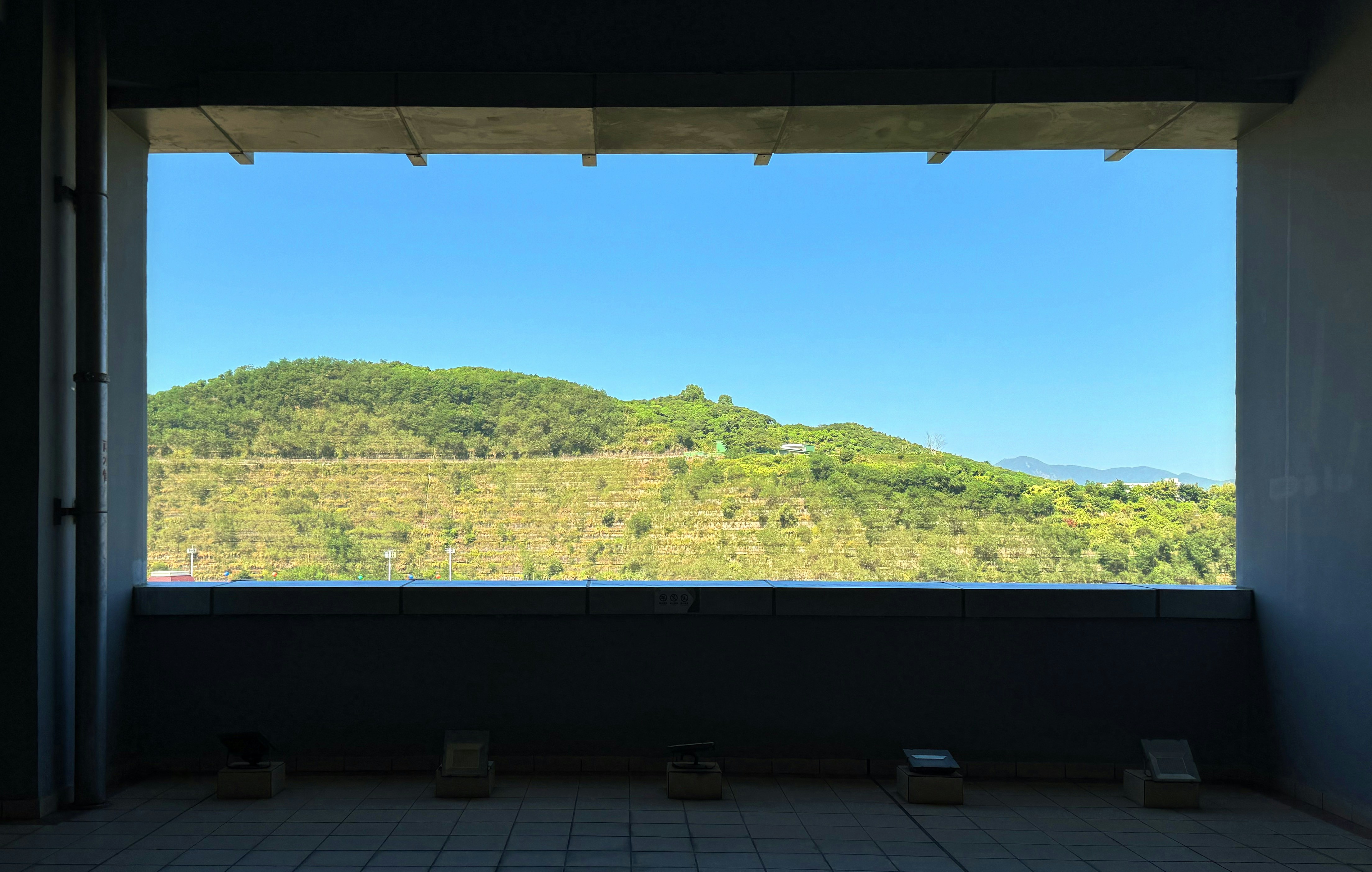 Horizon Framed by Shadow: Sunlit Hillscape Beyond a Window