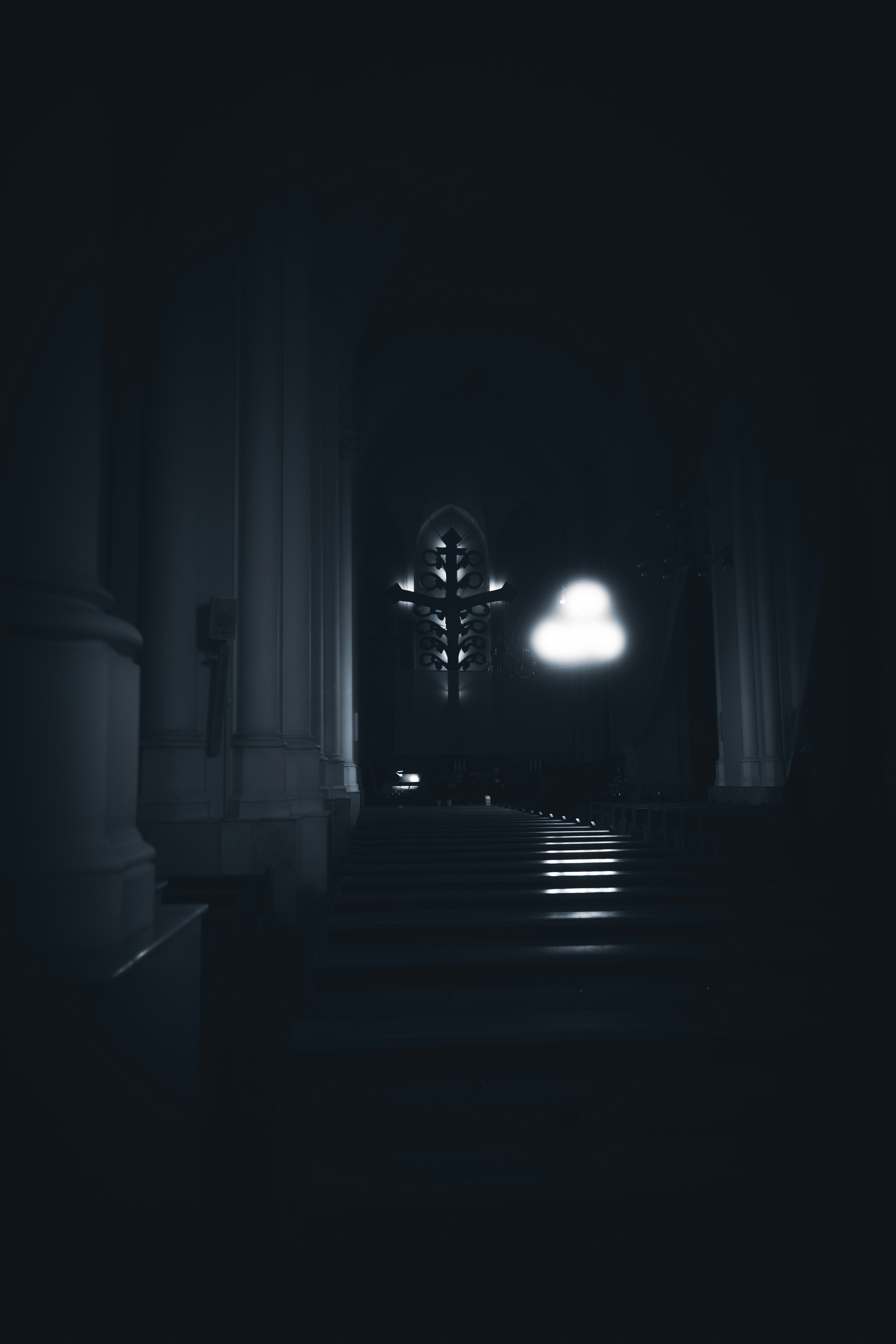 Hushed Aisle: A Glowing Cross at the End of a Shadowed Nave