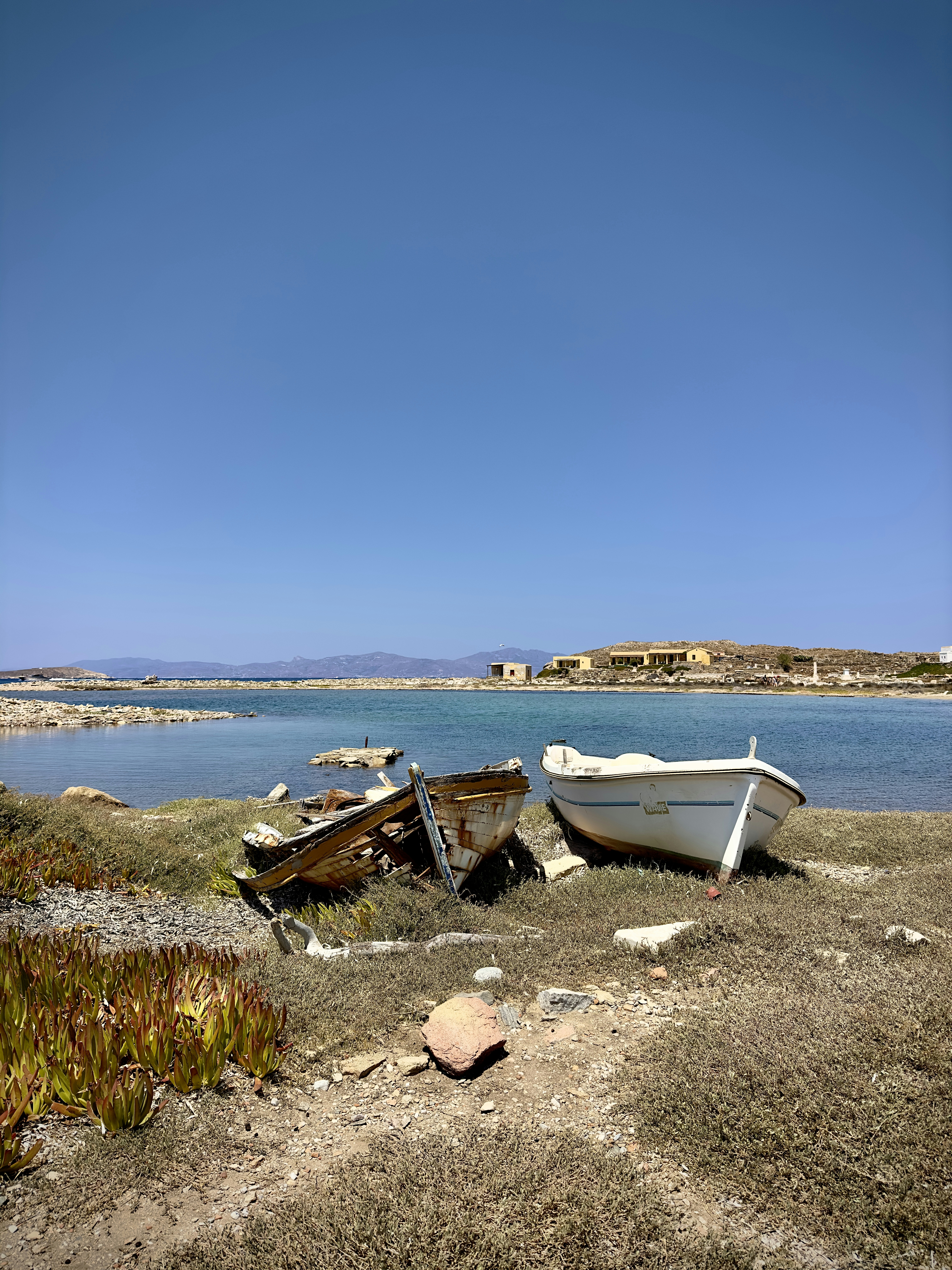 Quiet Shoreline Respite: Weathered Boats Rest by a Clear Sea