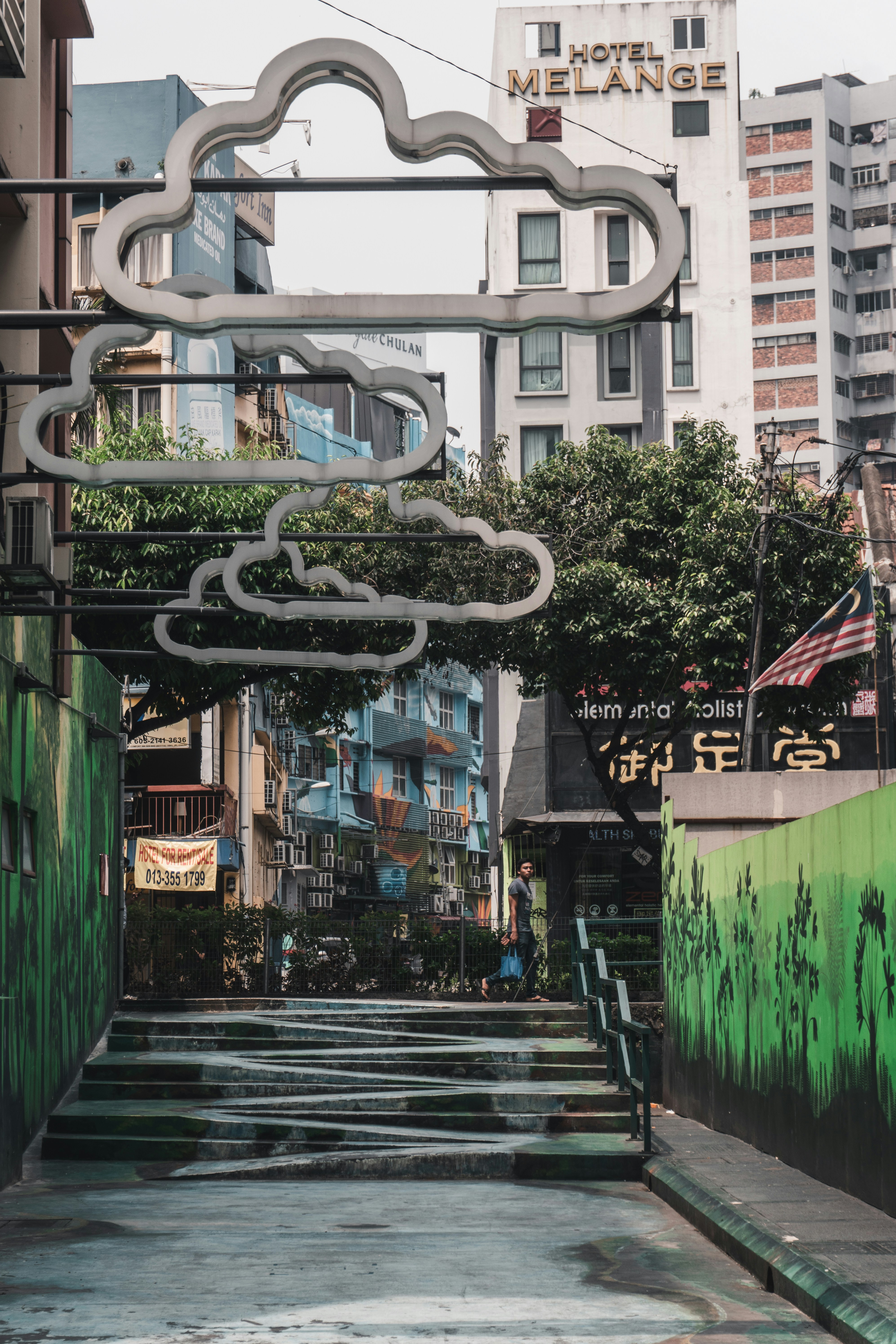 Cloud-Neon Arches Framing a City Stairwell Toward Hotel Melange