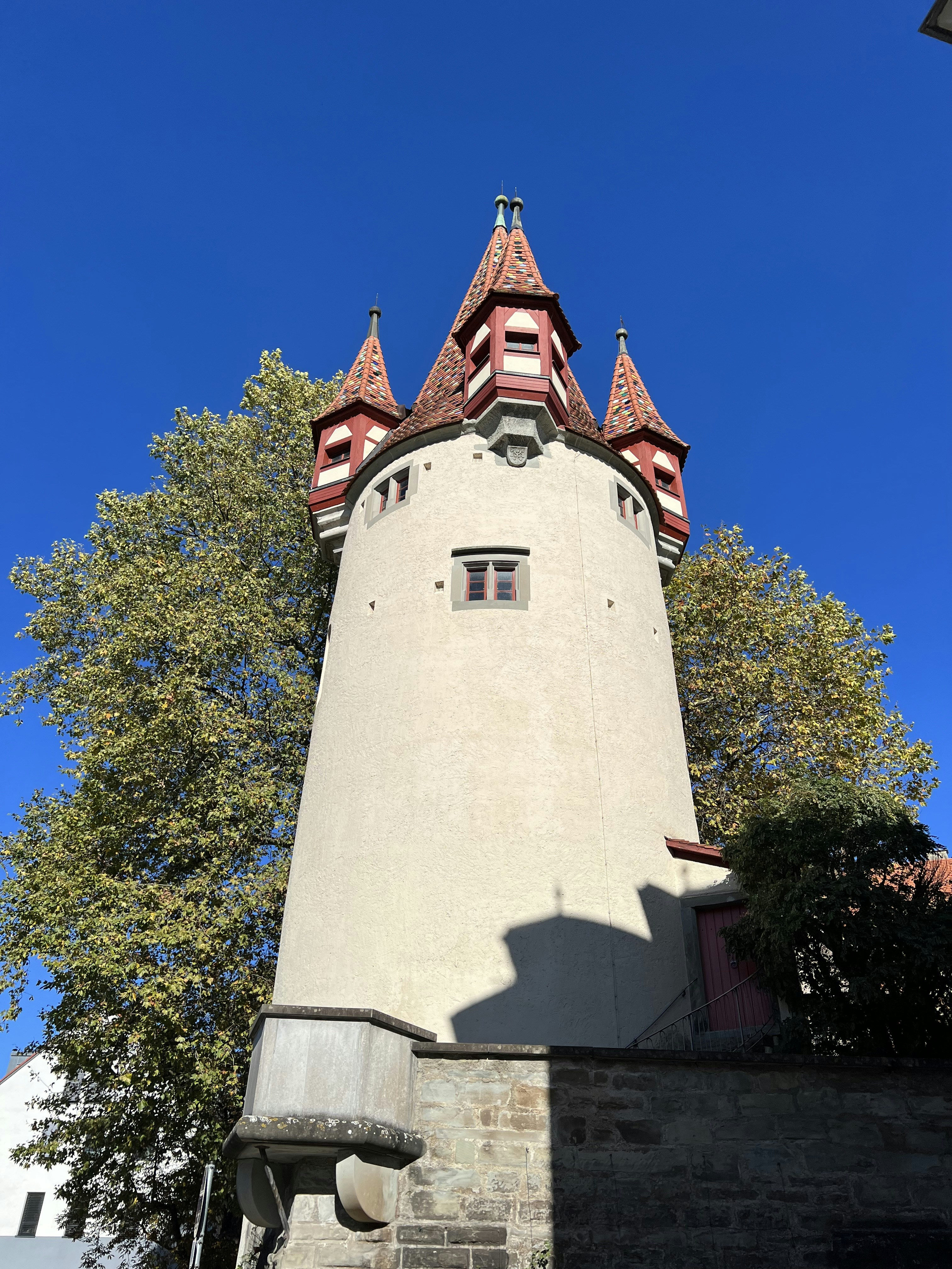 Crimson Turrets Crown a Sunlit Medieval Tower Against a Cerulean Sky