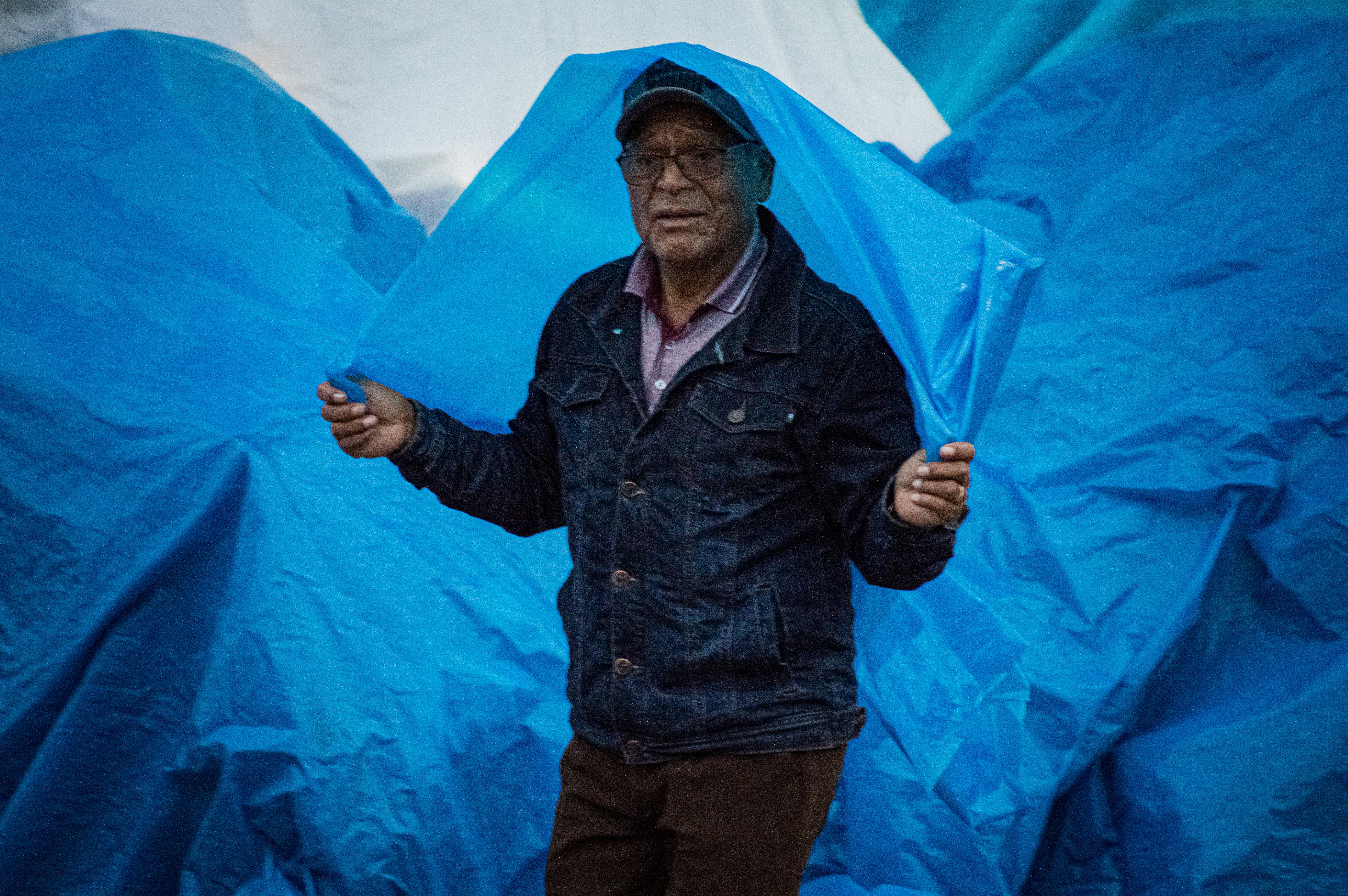 A man standing in front of a blue tarp photo – Free Coat Image on Unsplash