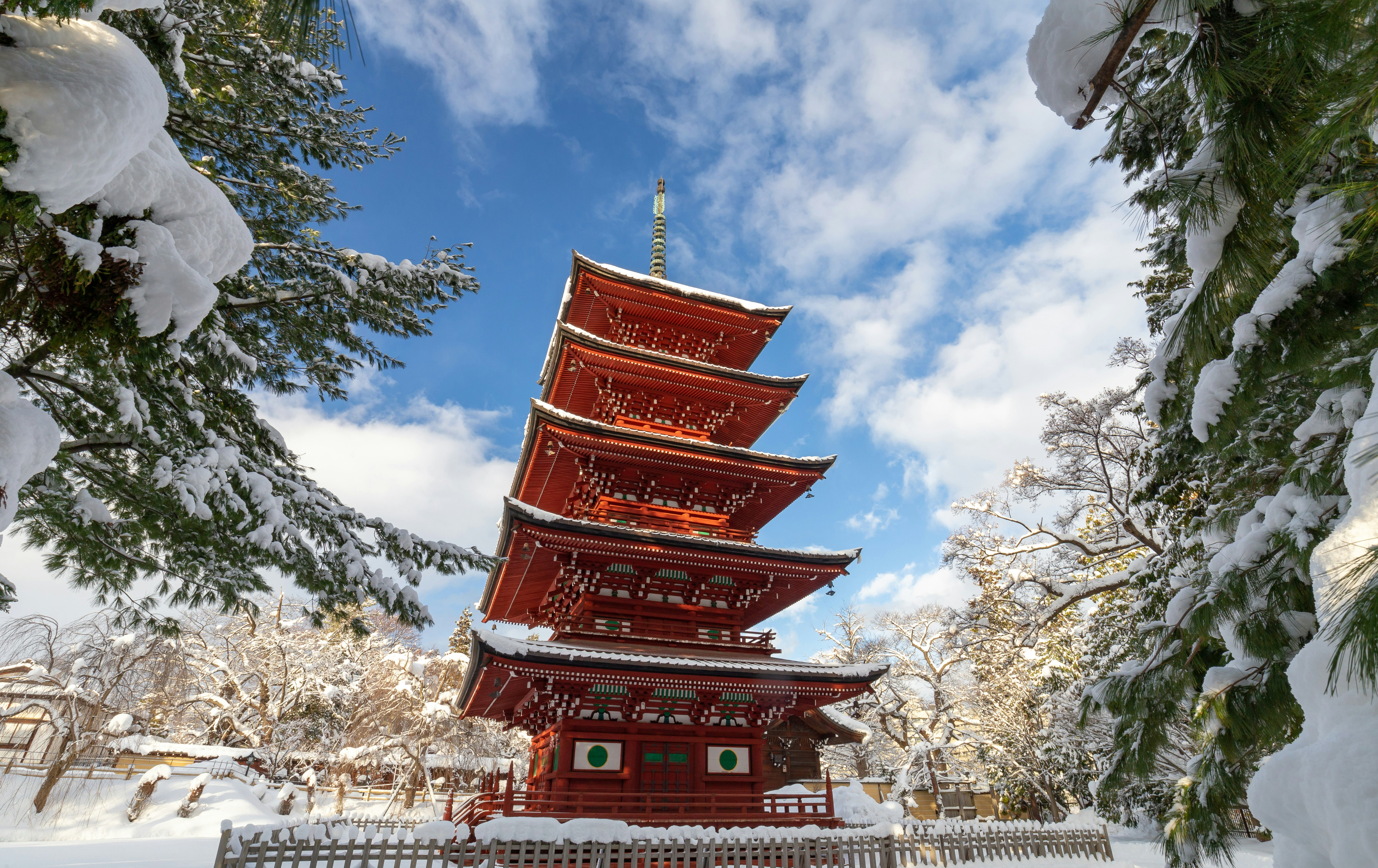 A tall red pagoda surrounded by snow covered trees photo – Free ...