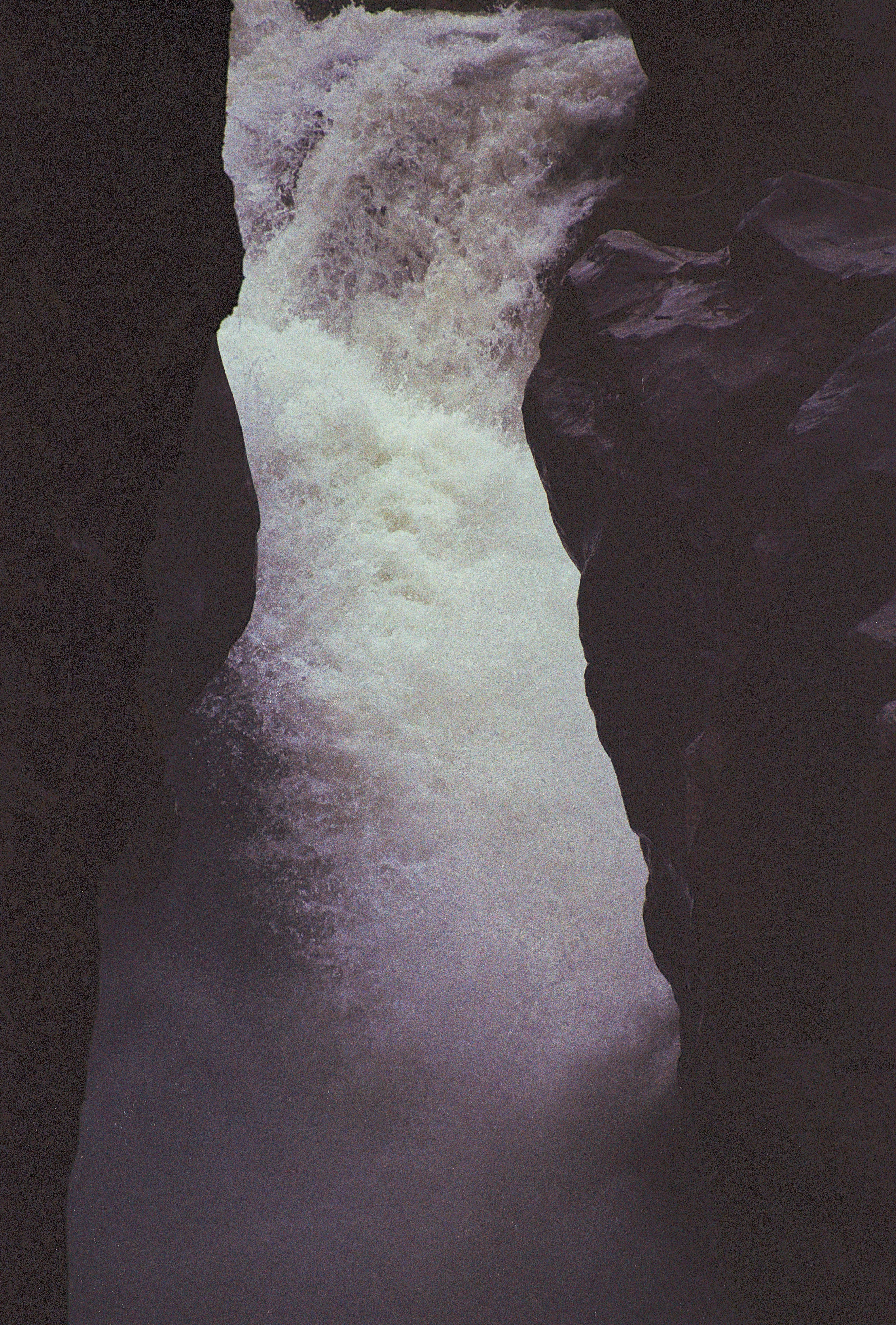 a man standing on a rock in front of a waterfall