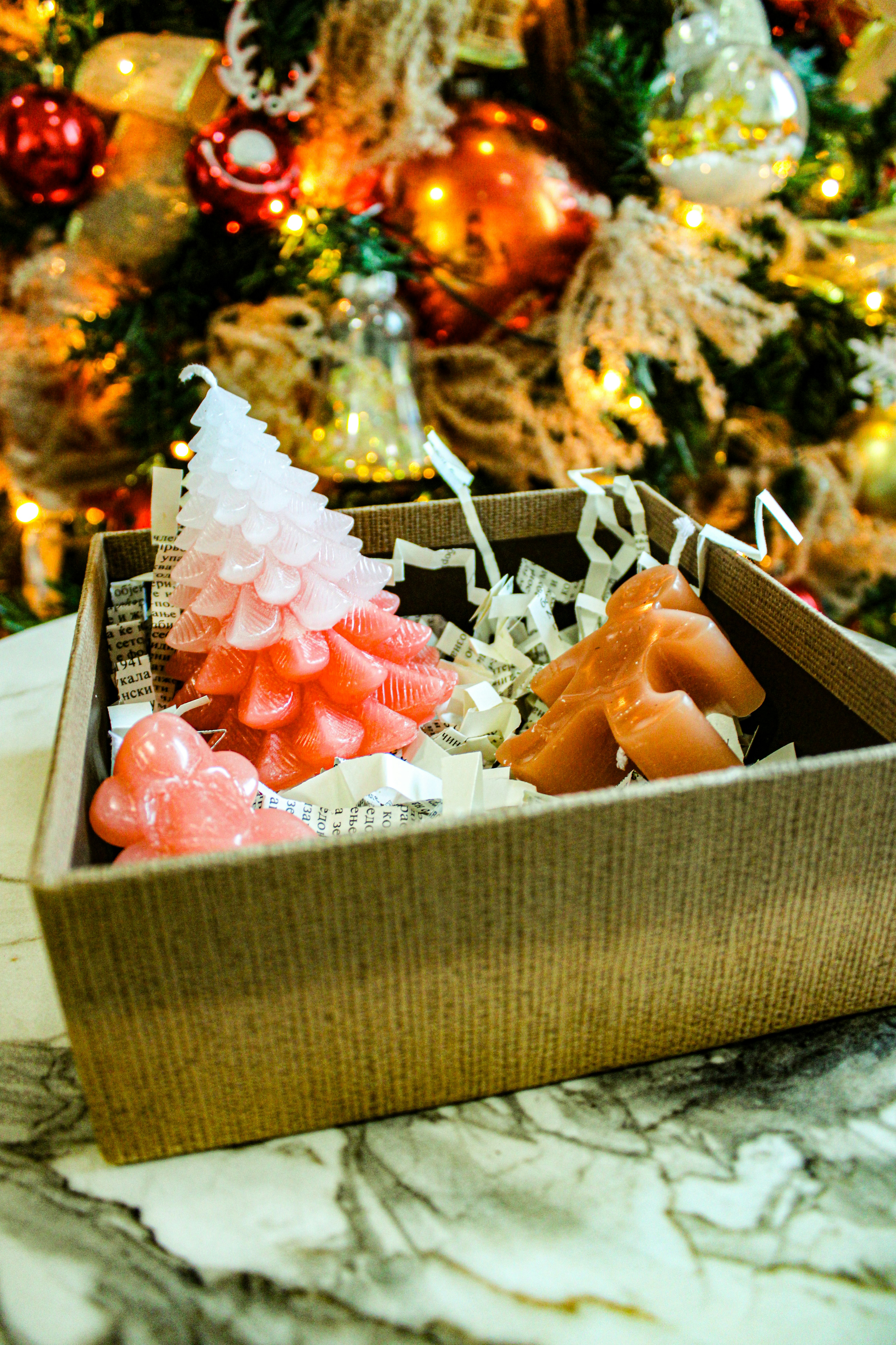 A box filled with assorted candies next to a christmas tree photo ...