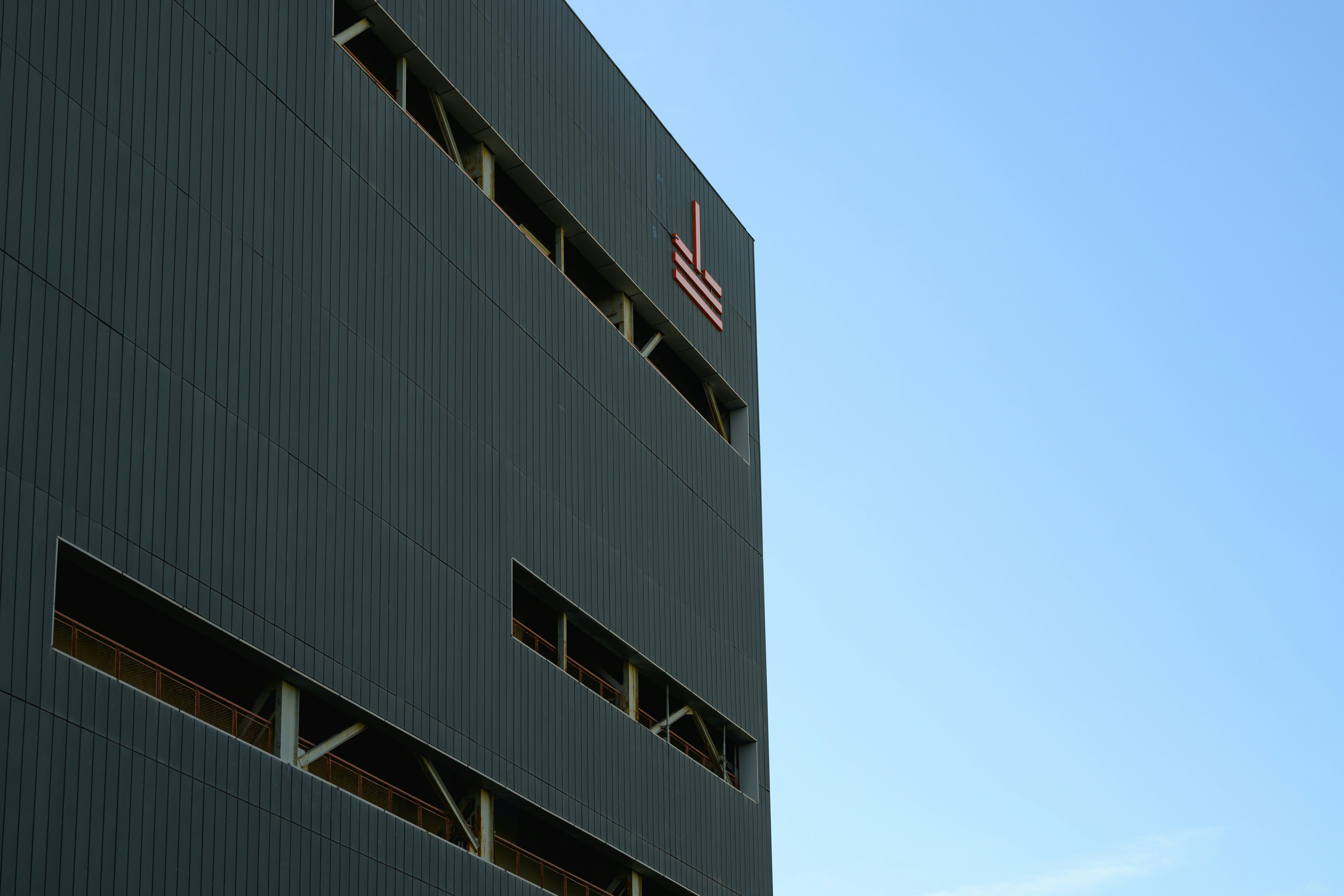 Red Emblem on a Monolithic Facade Under a Cerulean Sky