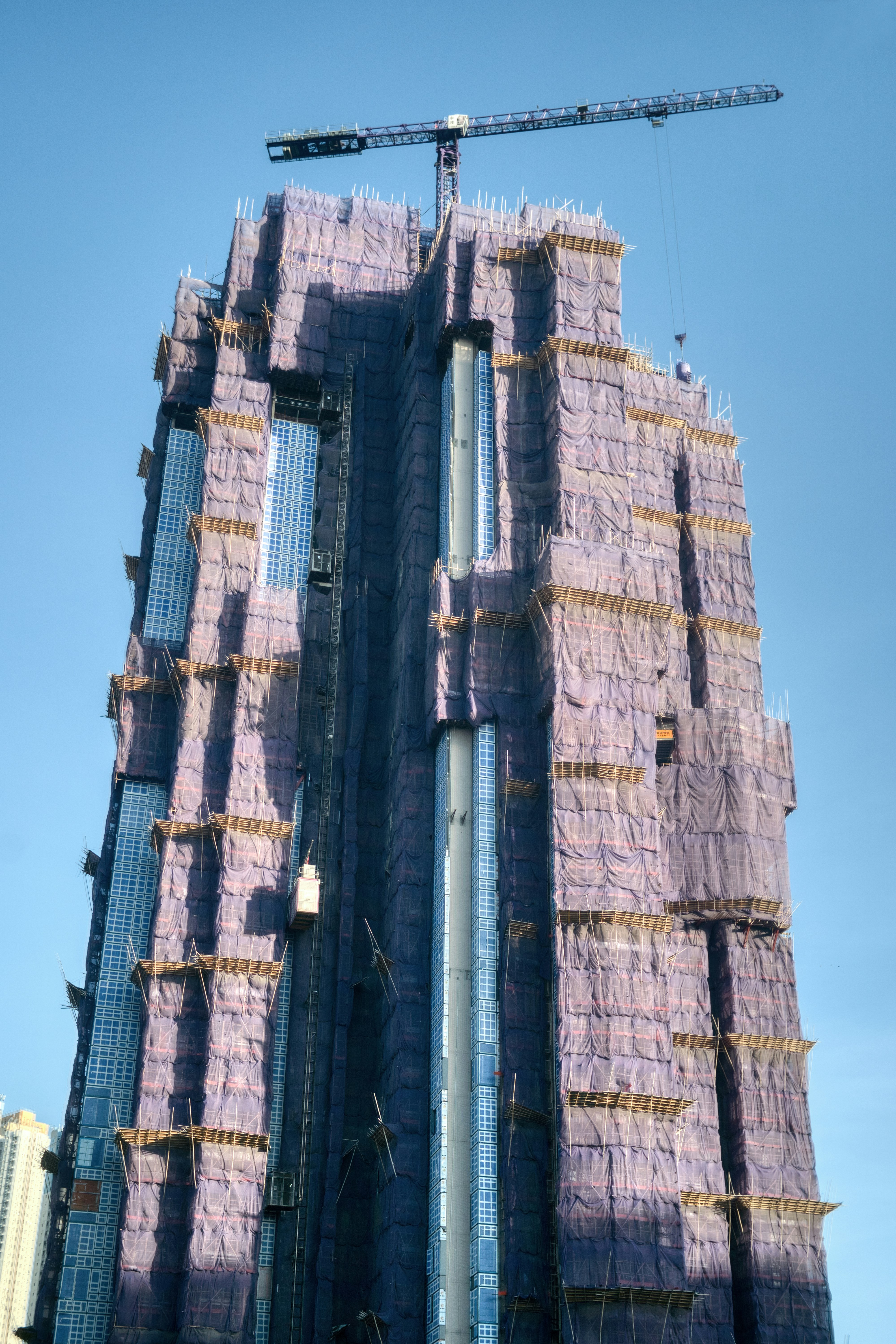 Purple Sheath Rising: A Crane-Topped Tower Under Construction
