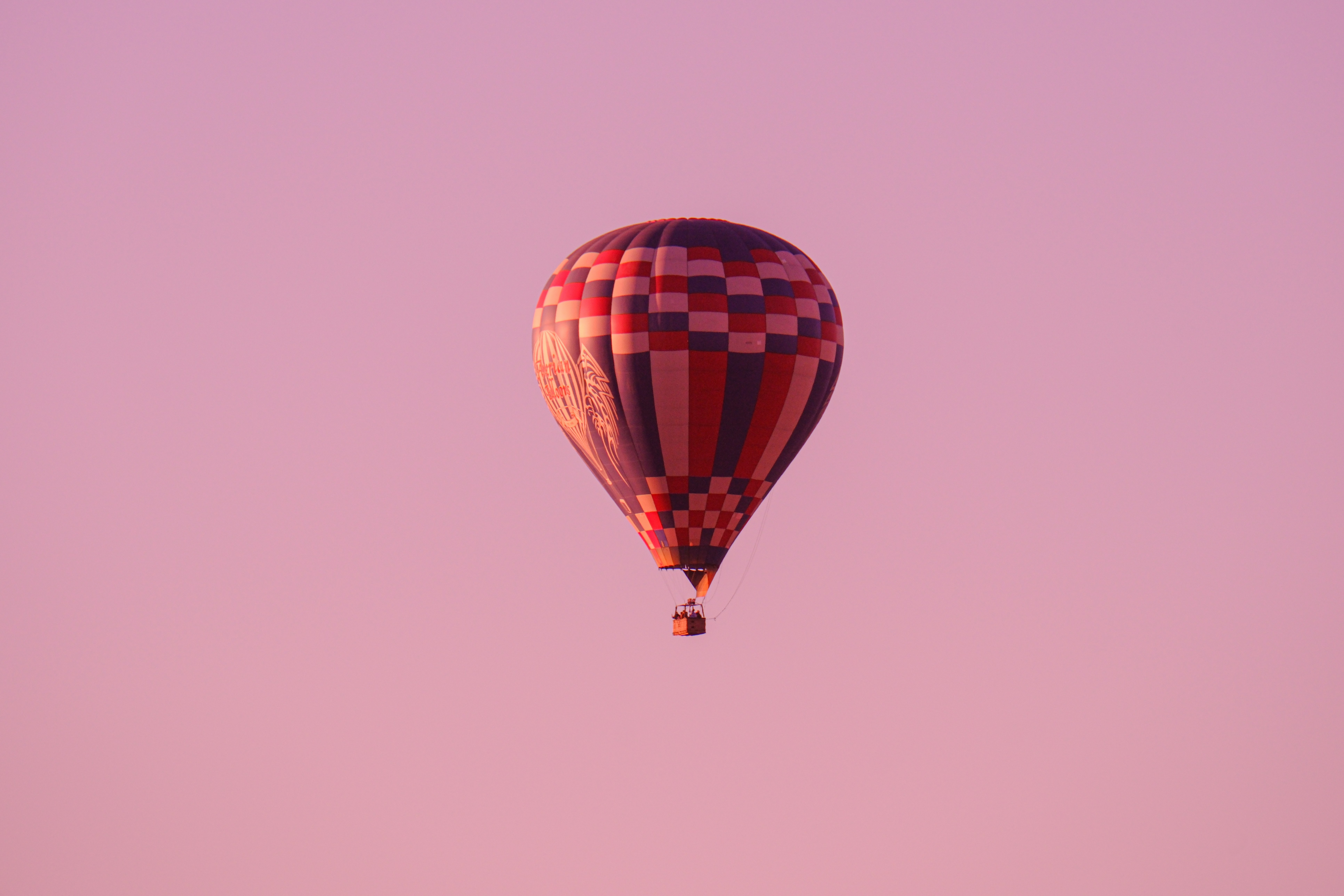 Crimson-Checkered Balloon Drifting Through a Blush Dusk Sky
