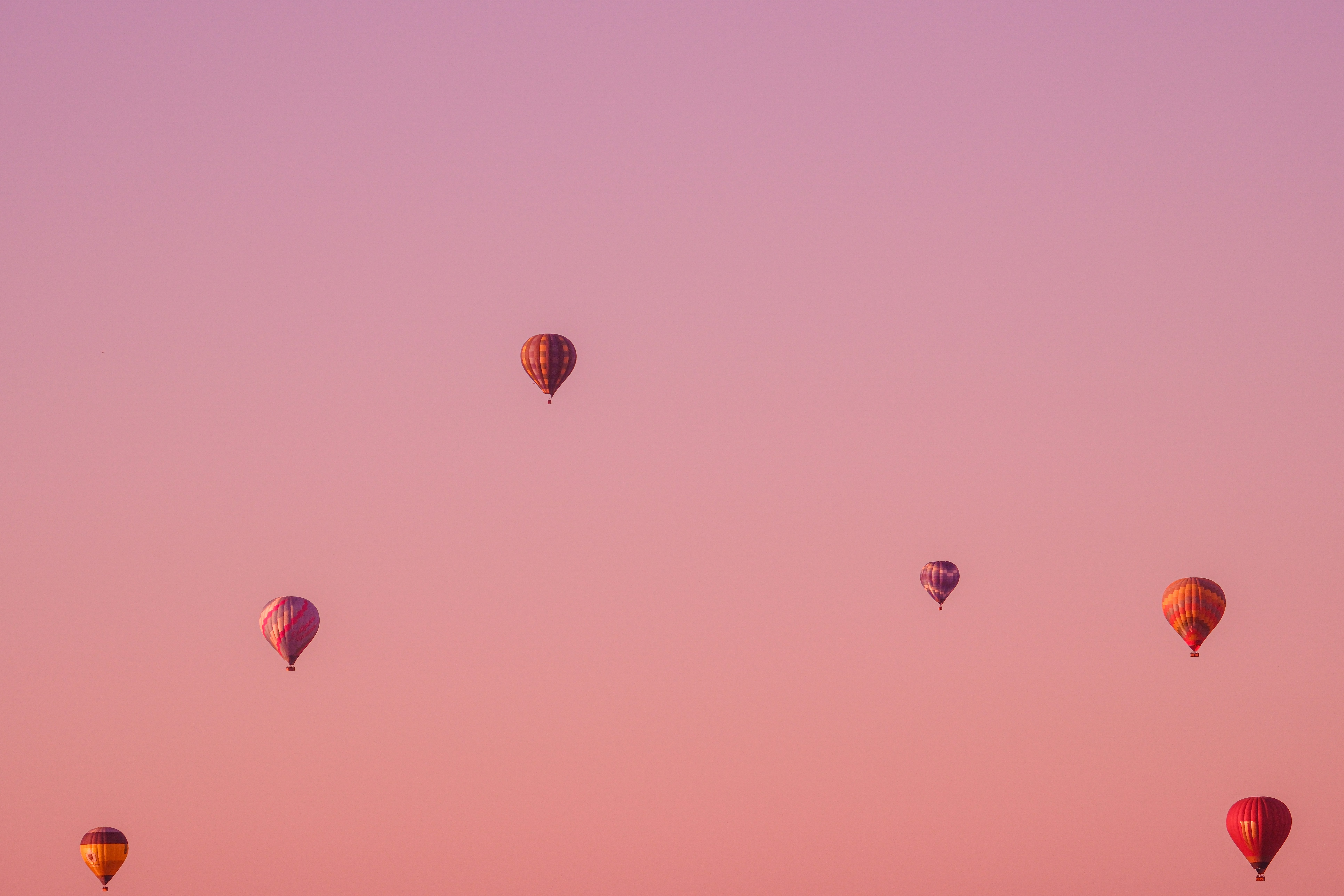 Whispers on the Horizon: Balloons Drifting Against a Blush Sky