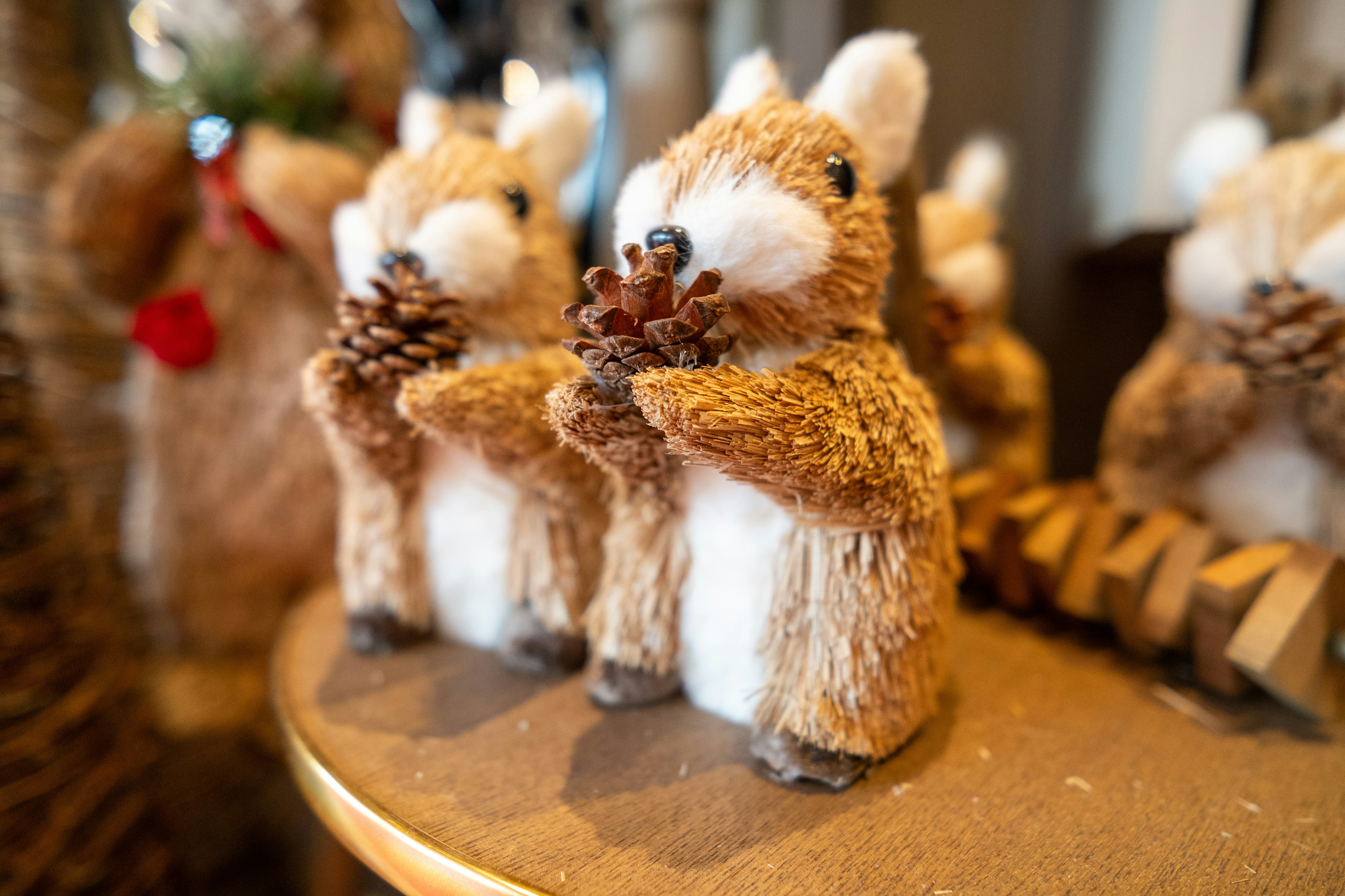 Crafted squirrel figurines holding pinecones on a wooden table.