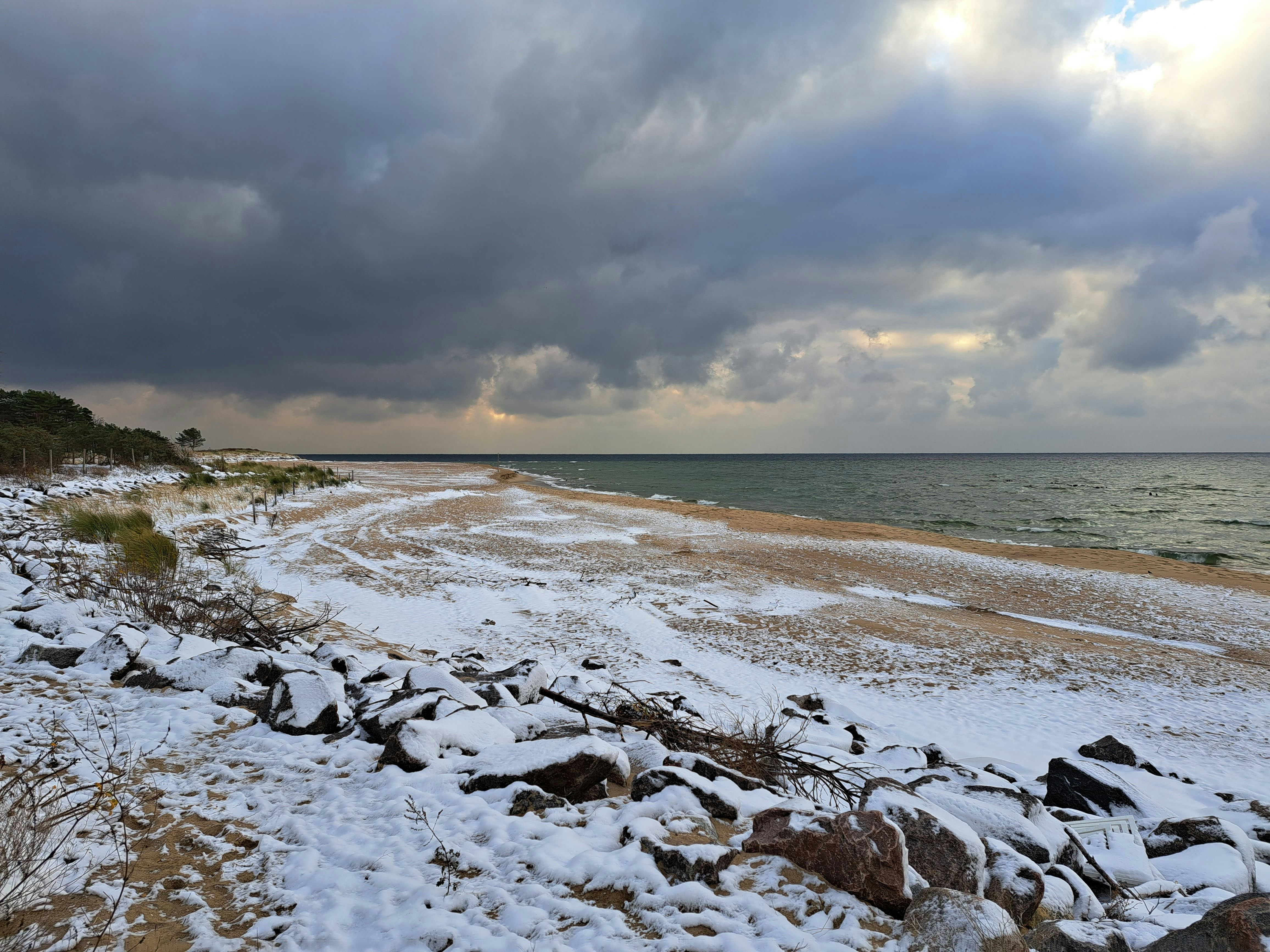 A sandy beach covered in snow under a cloudy sky photo – Free Nature ...