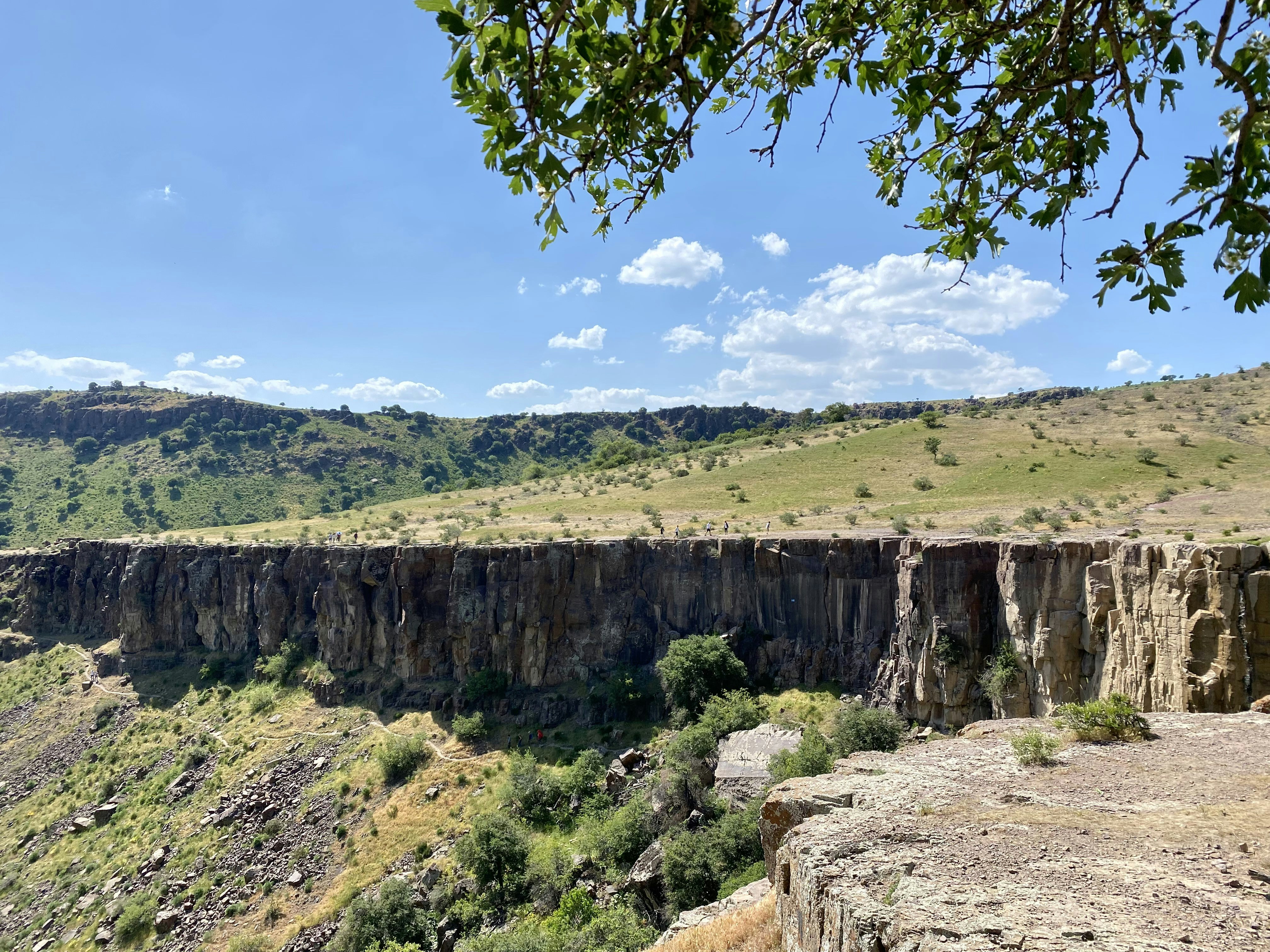 A view of a rocky cliff with a valley in the background photo – Free ...