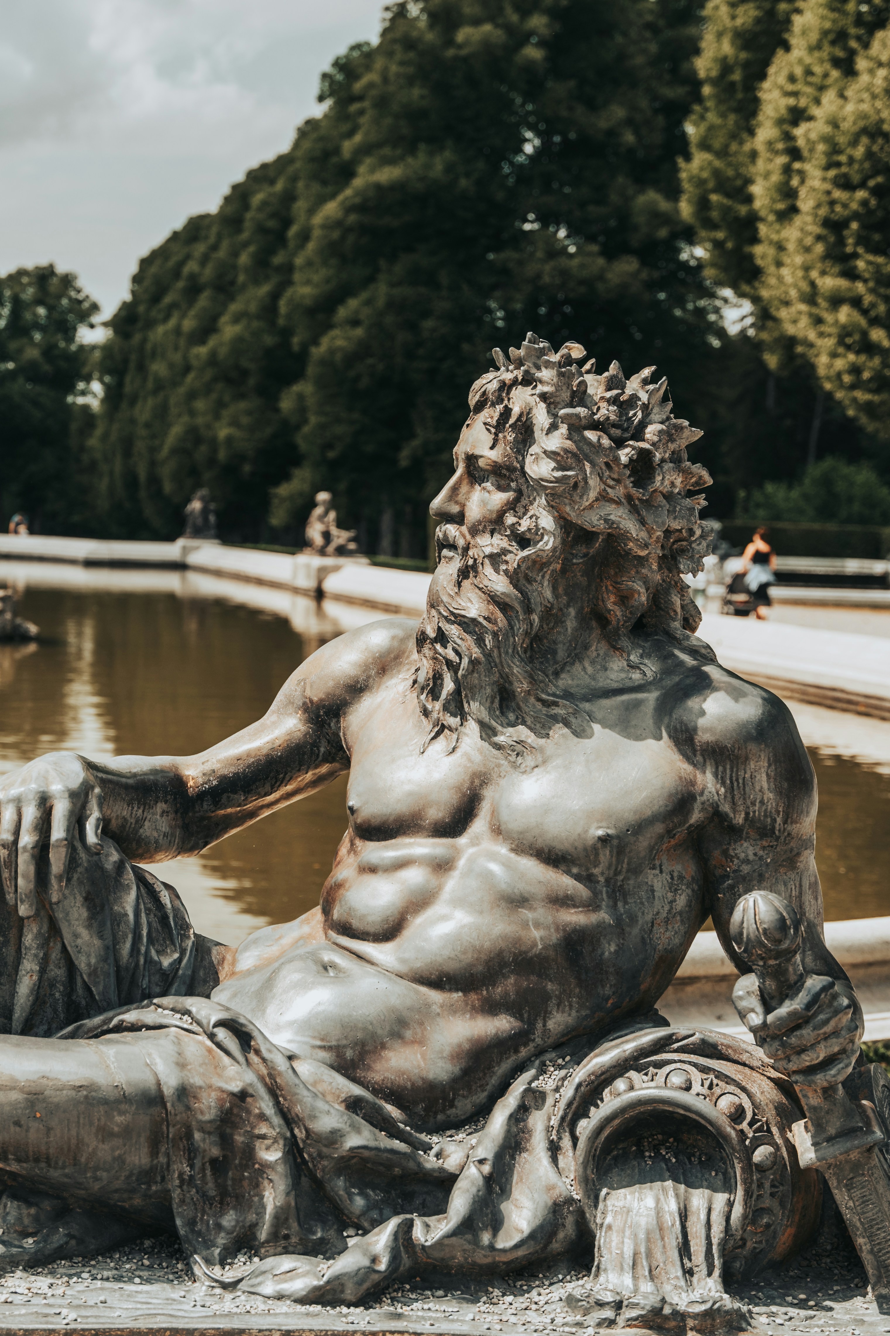 Giant of the Fountain: A bronze titan reclines at the edge of the pool