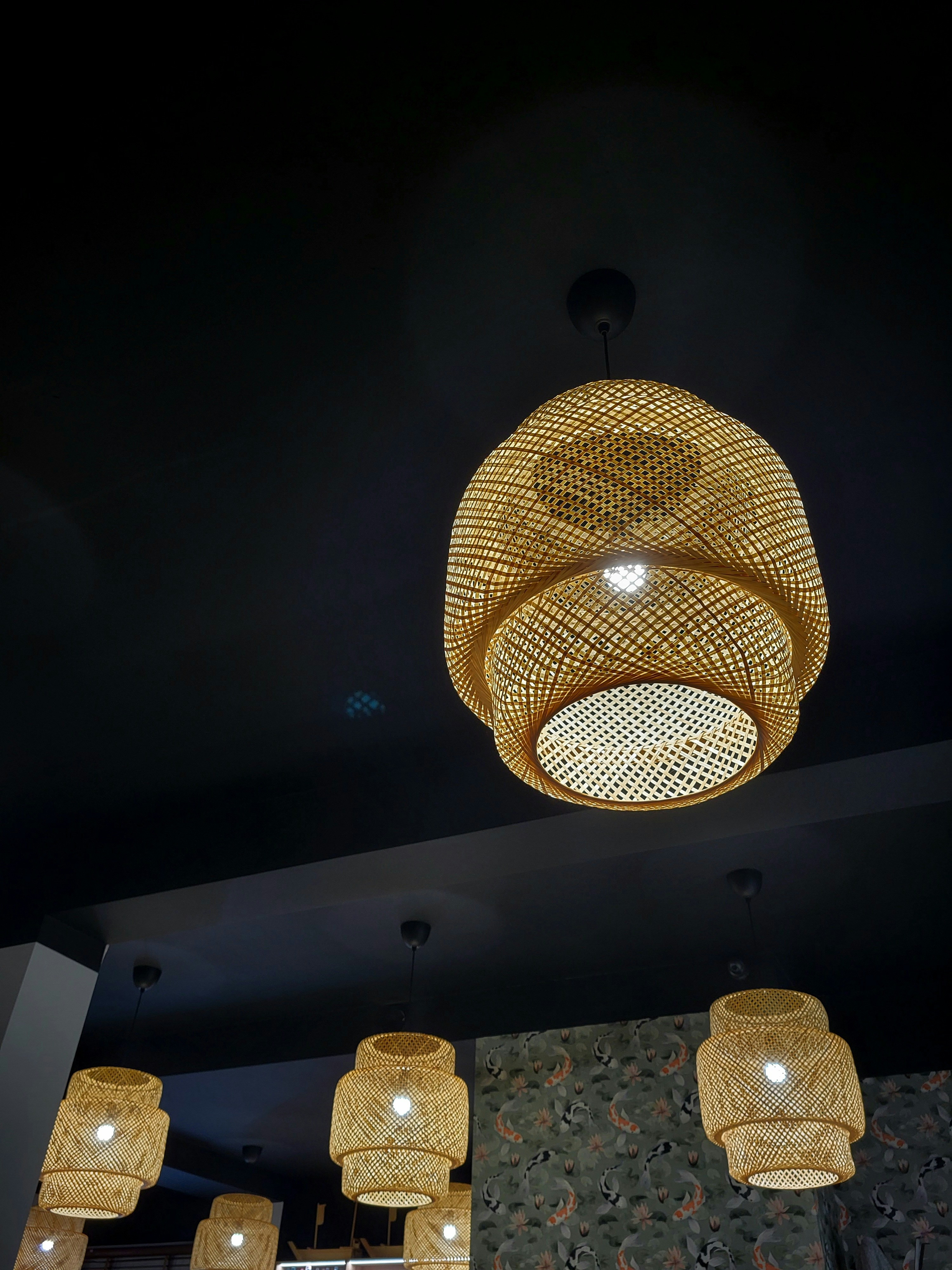 Intricately woven pendant lights hanging from a dark ceiling, casting soft illumination in a cozy setting.