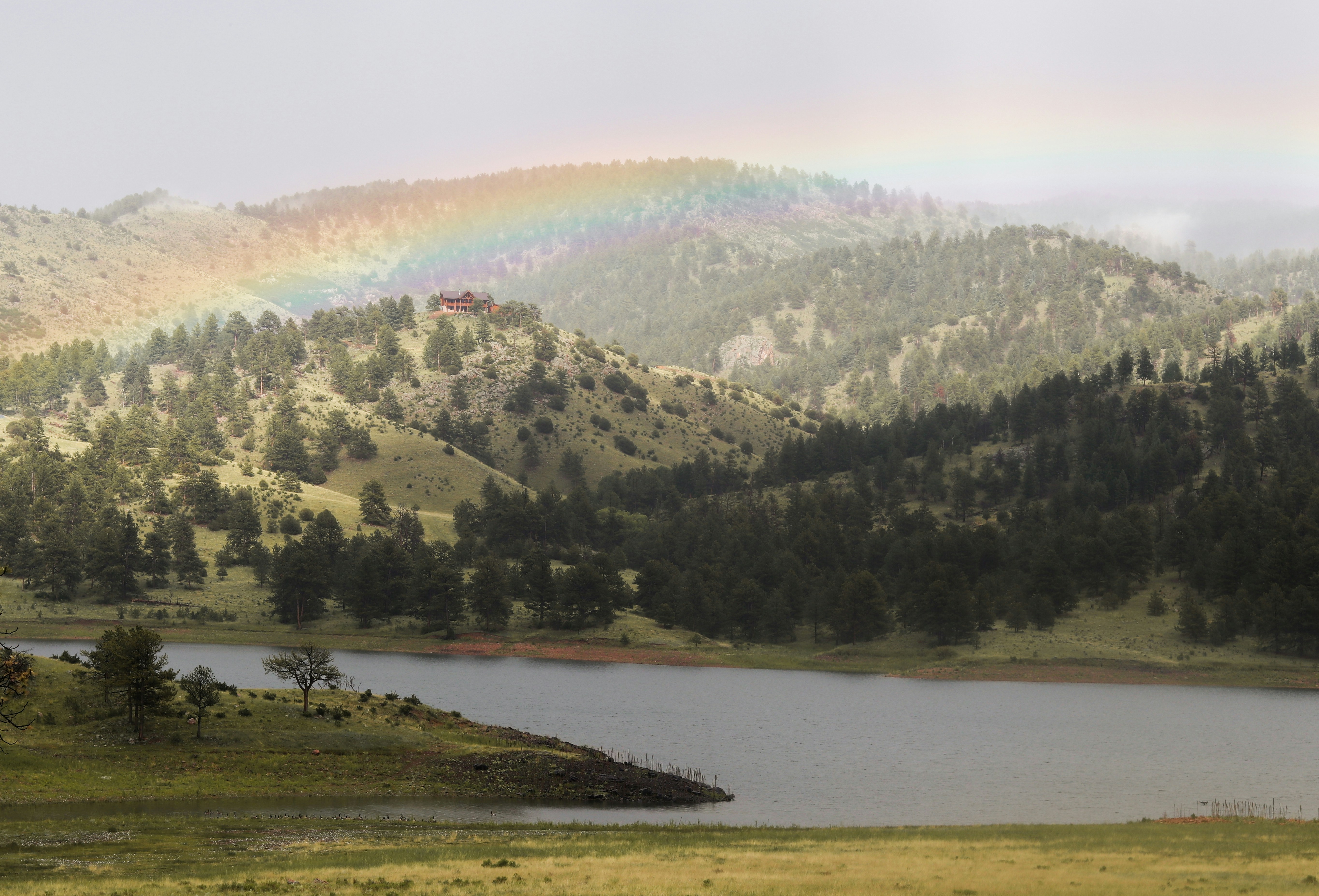 A rainbow in the sky over a lake and mountains photo – Free Colorado ...