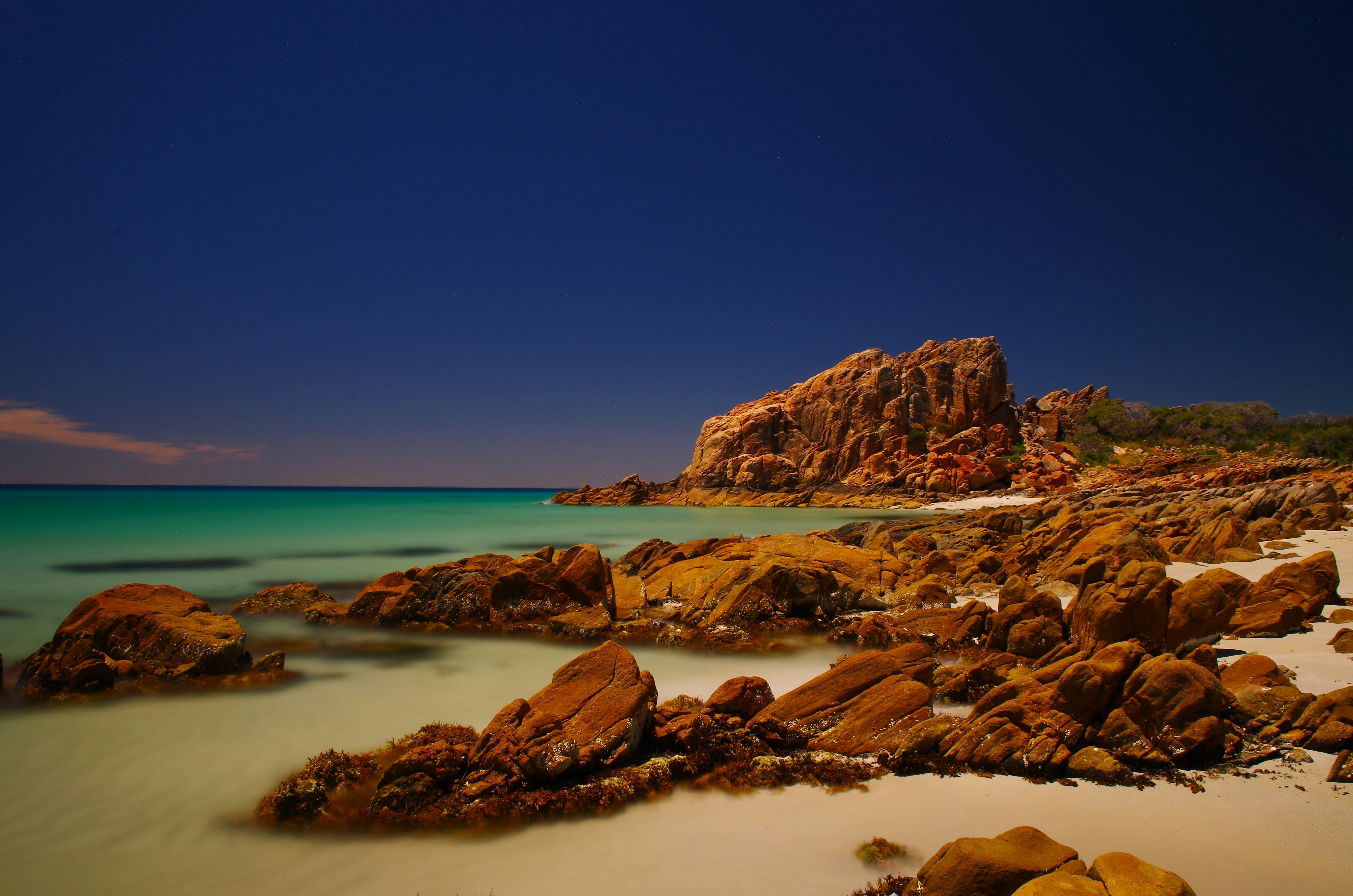 Rocky coastline under a deep blue sky with calm turquoise waters.