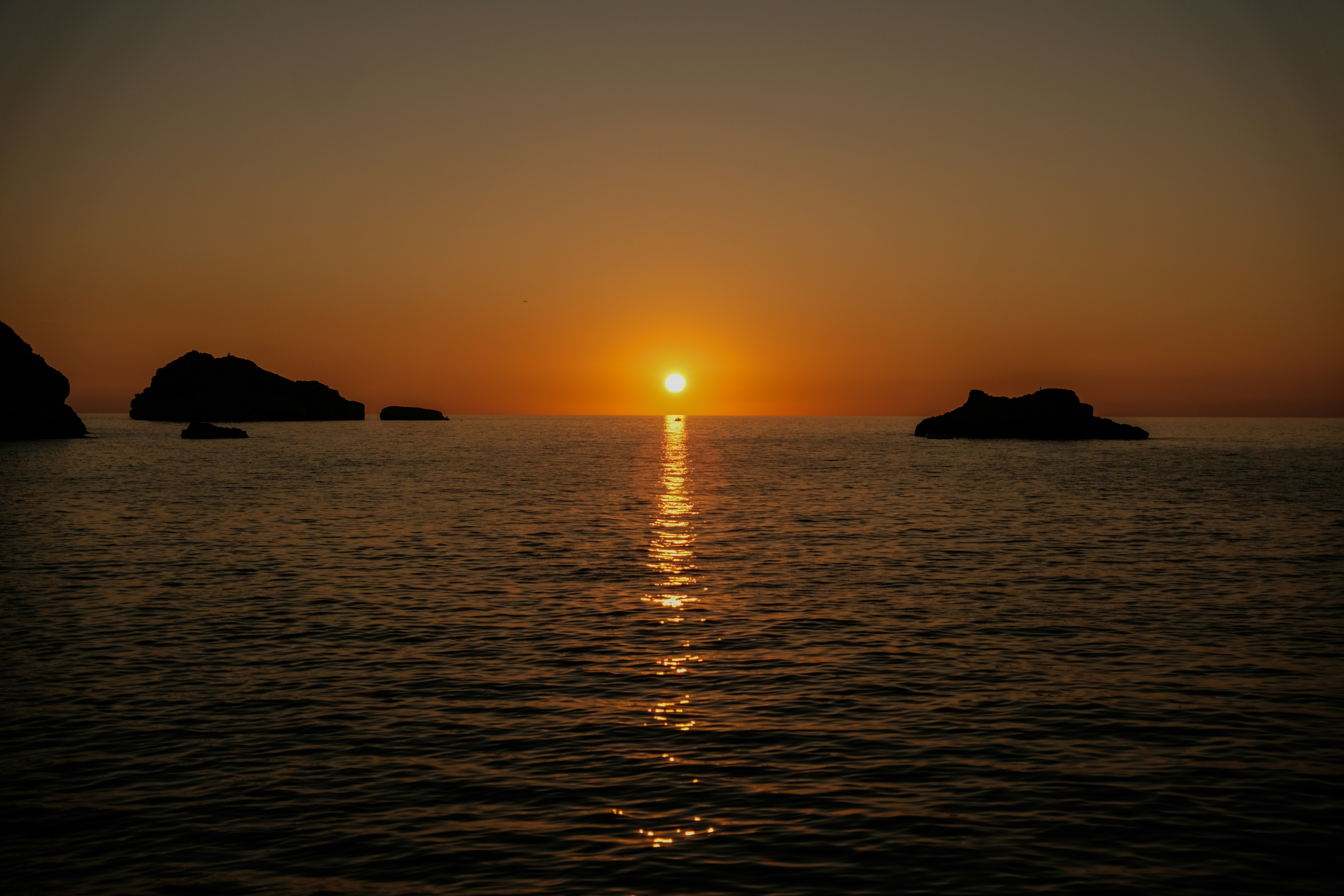 Foto El sol se está poniendo sobre el océano con rocas en el agua ...