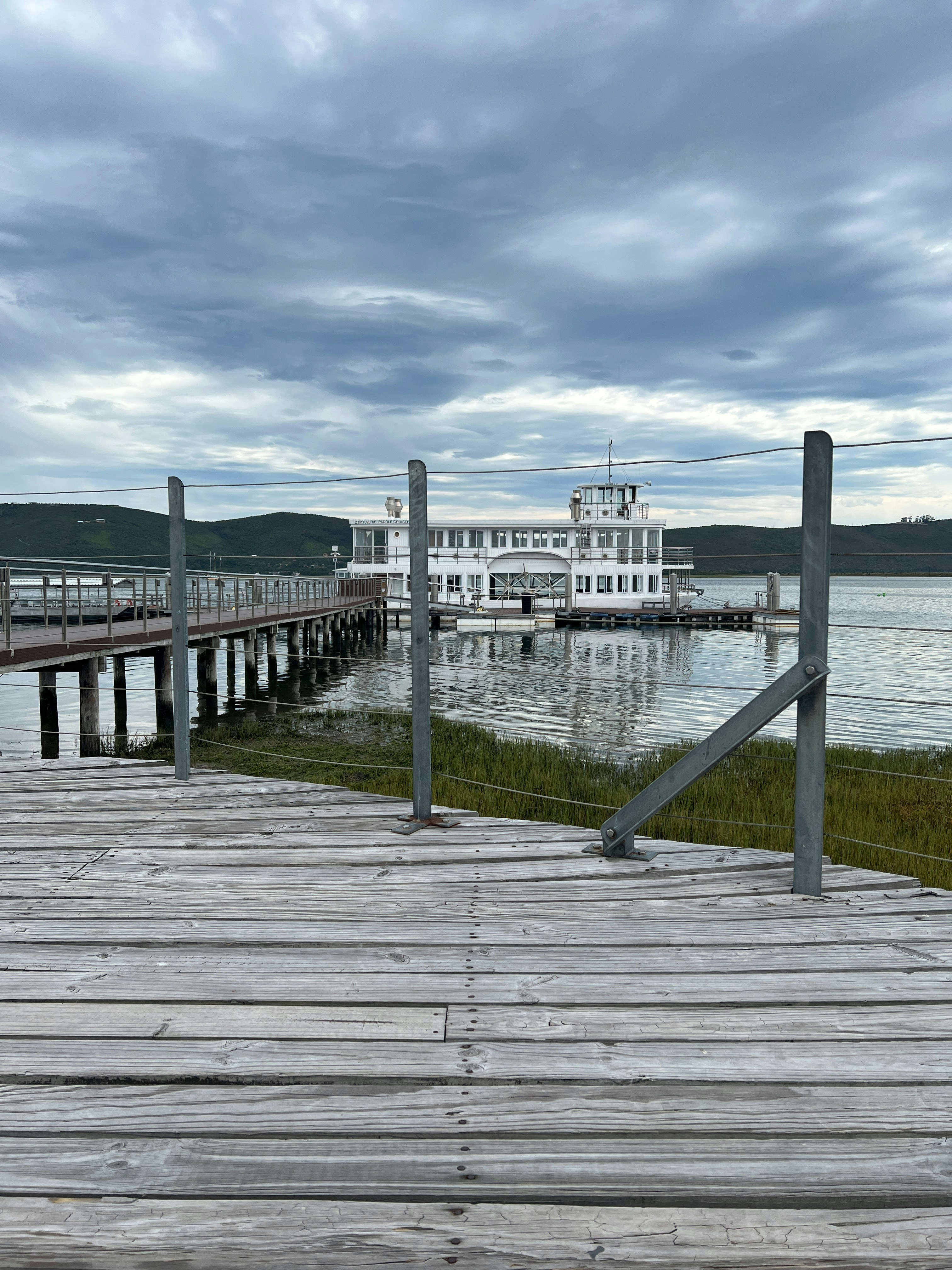 Symmetry on the Pier: A Quiet White Riverboat Framed by Weathered Planks