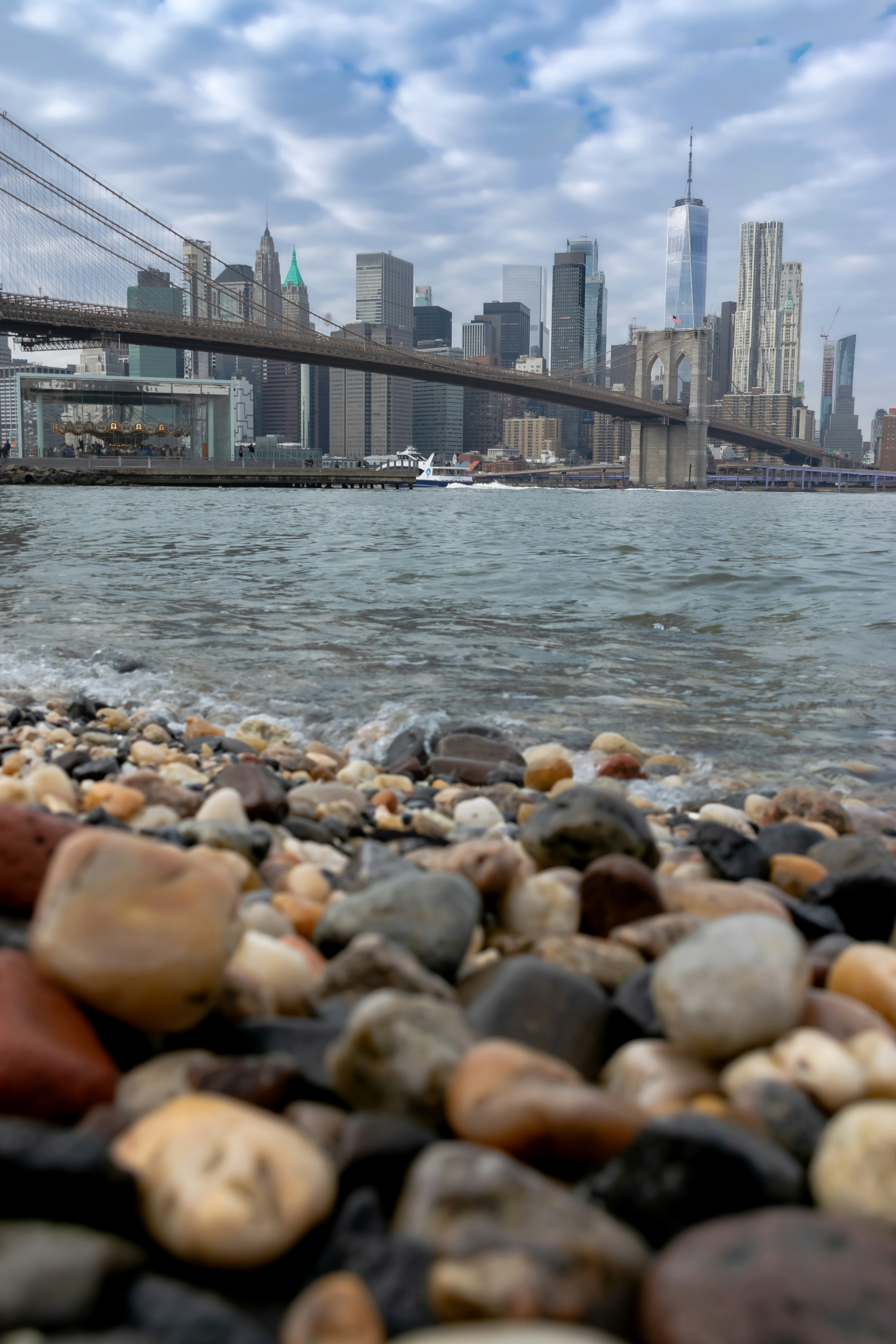 Pebble Threshold: Brooklyn Bridge Framing Manhattan's Cloudy Skyline