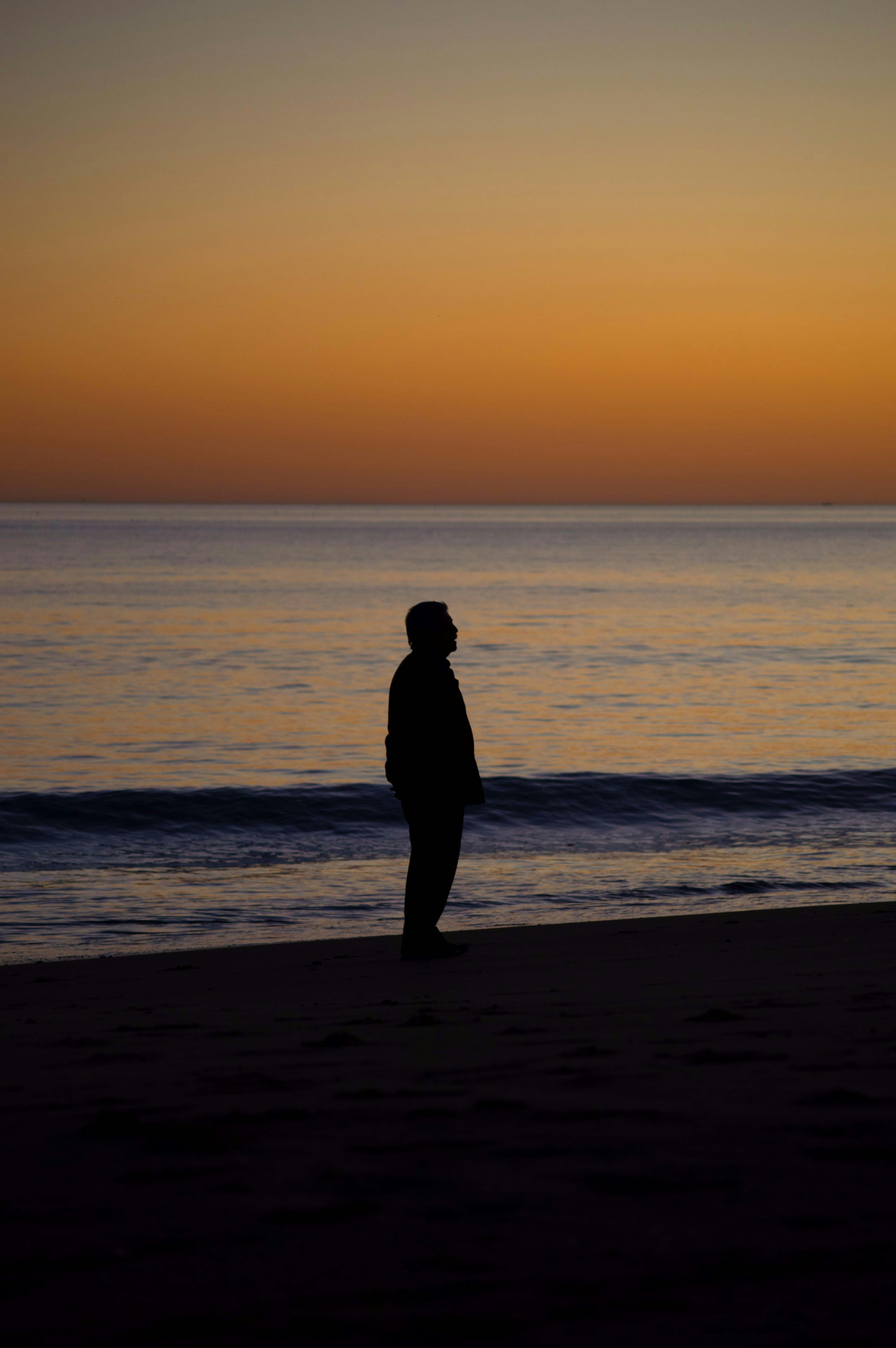 A person standing on a beach at sunset photo – Free Lepe Image on Unsplash