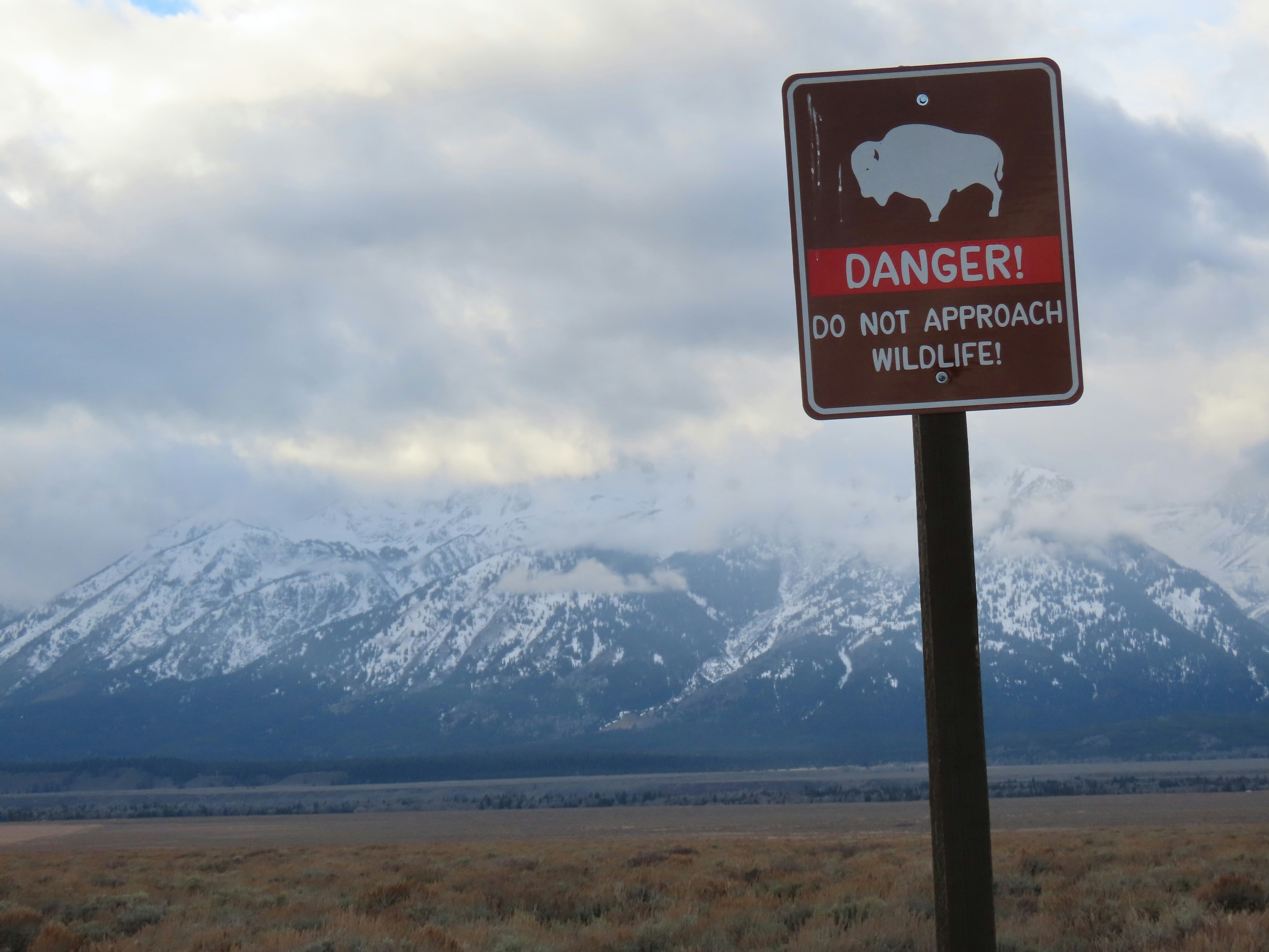 Danger Sign Framing Snow-Capped Range Over a Wind-Swept Plain