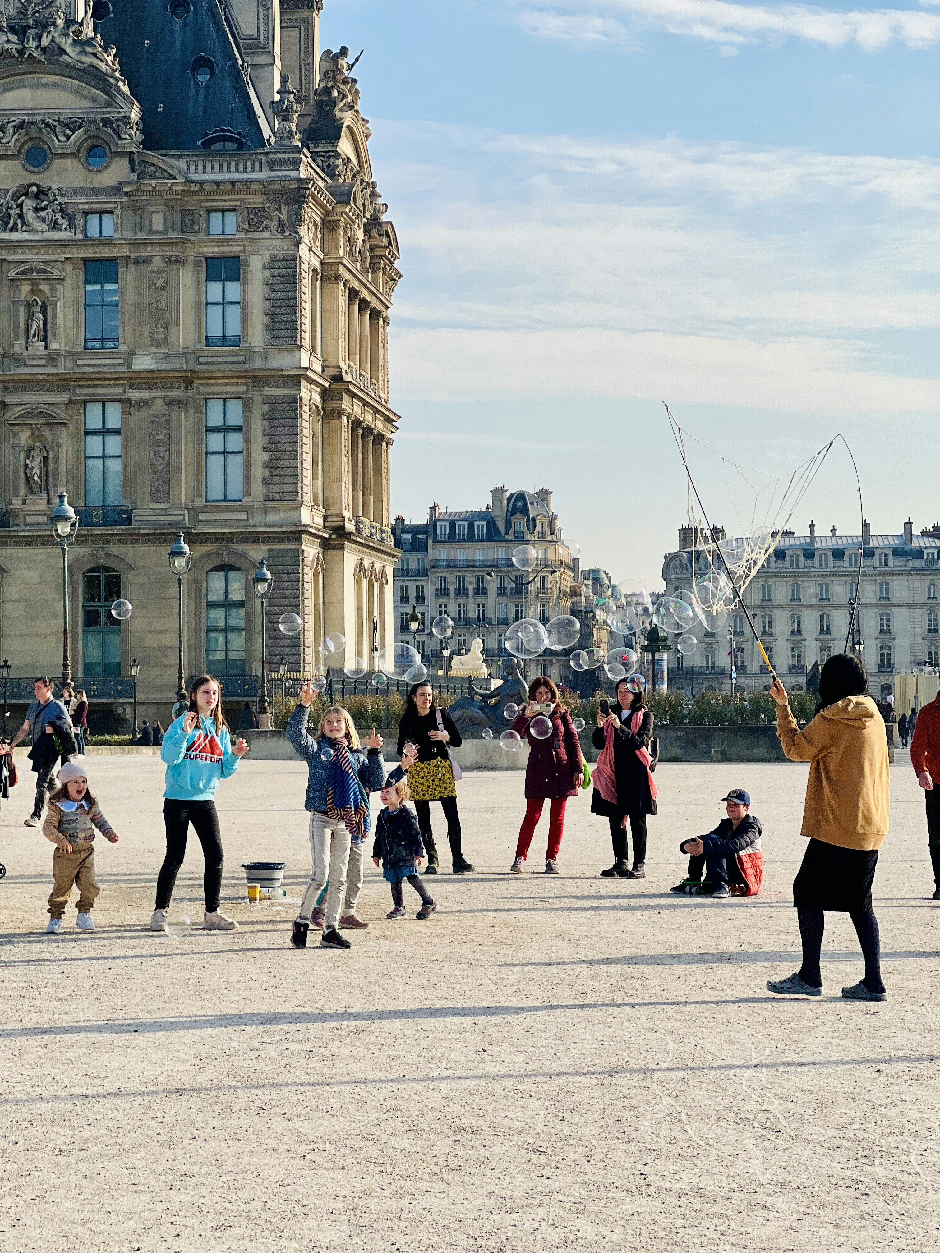 a group of people flying kites in front of a building