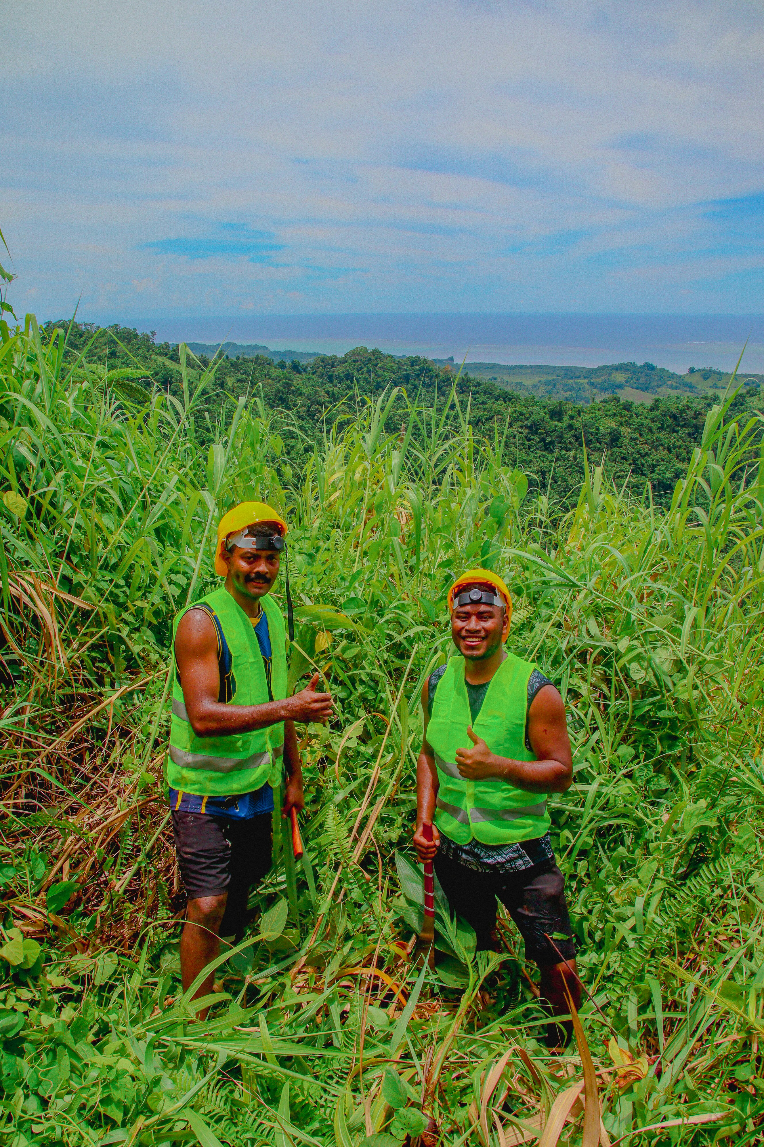 Neon Vests Above the Grassline: Two Surveyors with Ocean Horizon