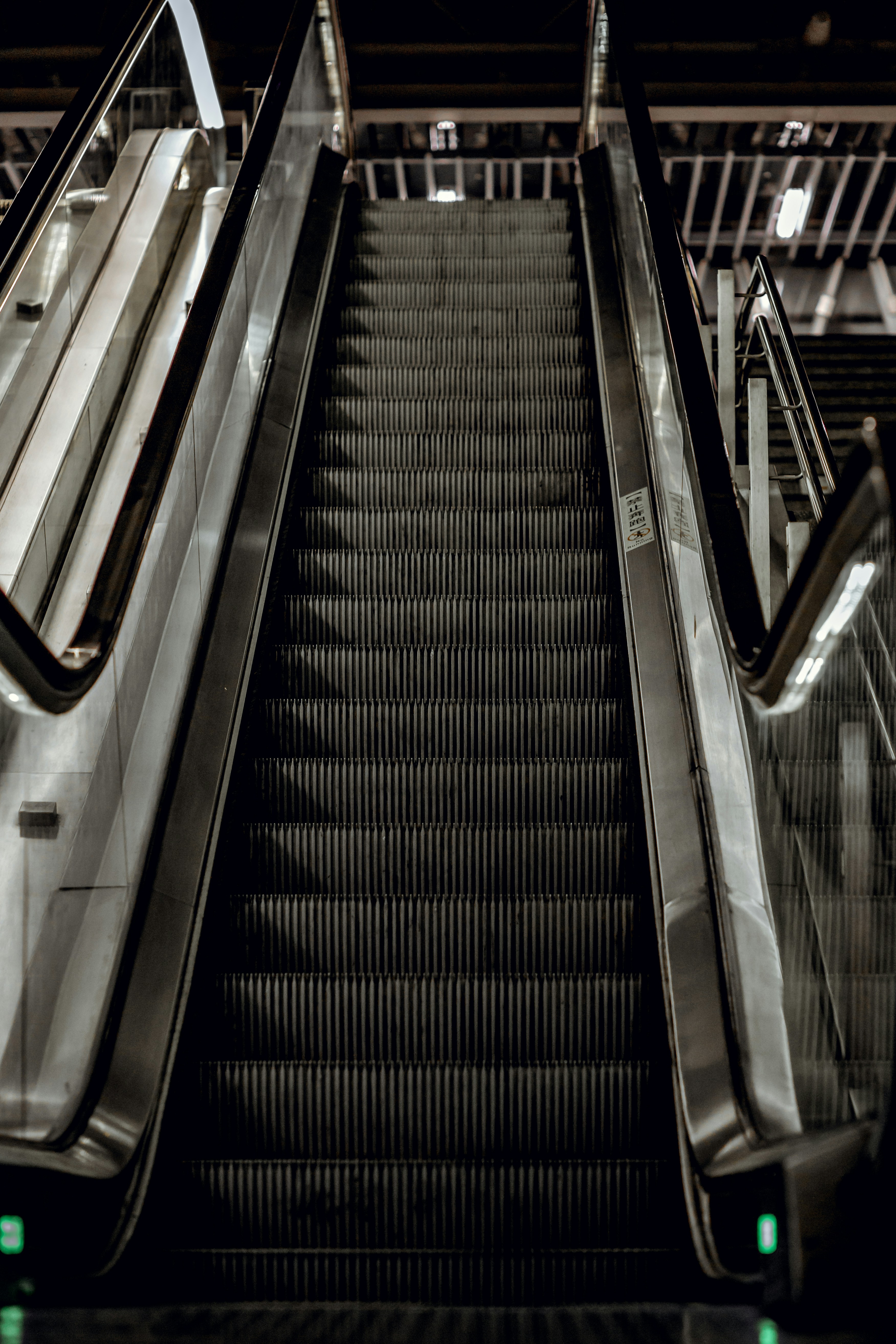 A close-up view of an escalator leading upwards, framed by sleek glass railings and illuminated by ambient lighting.