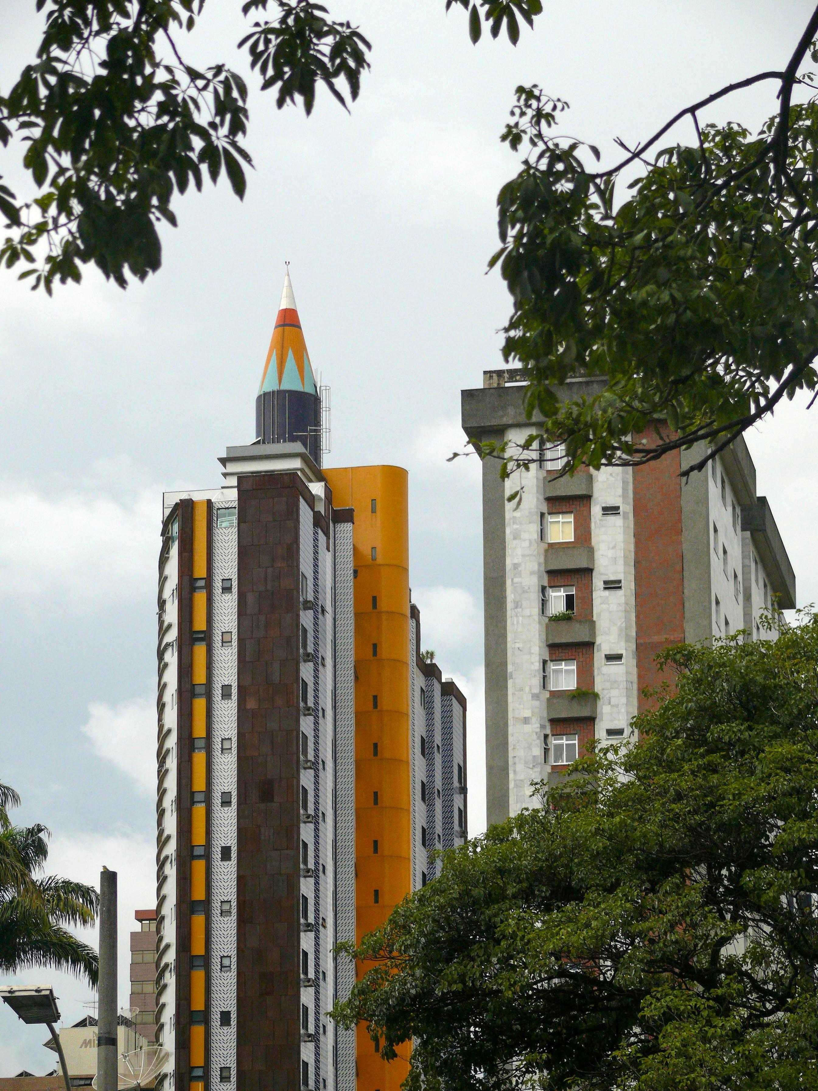 Vibrant high-rise buildings intermingled with lush greenery against a cloudy sky.