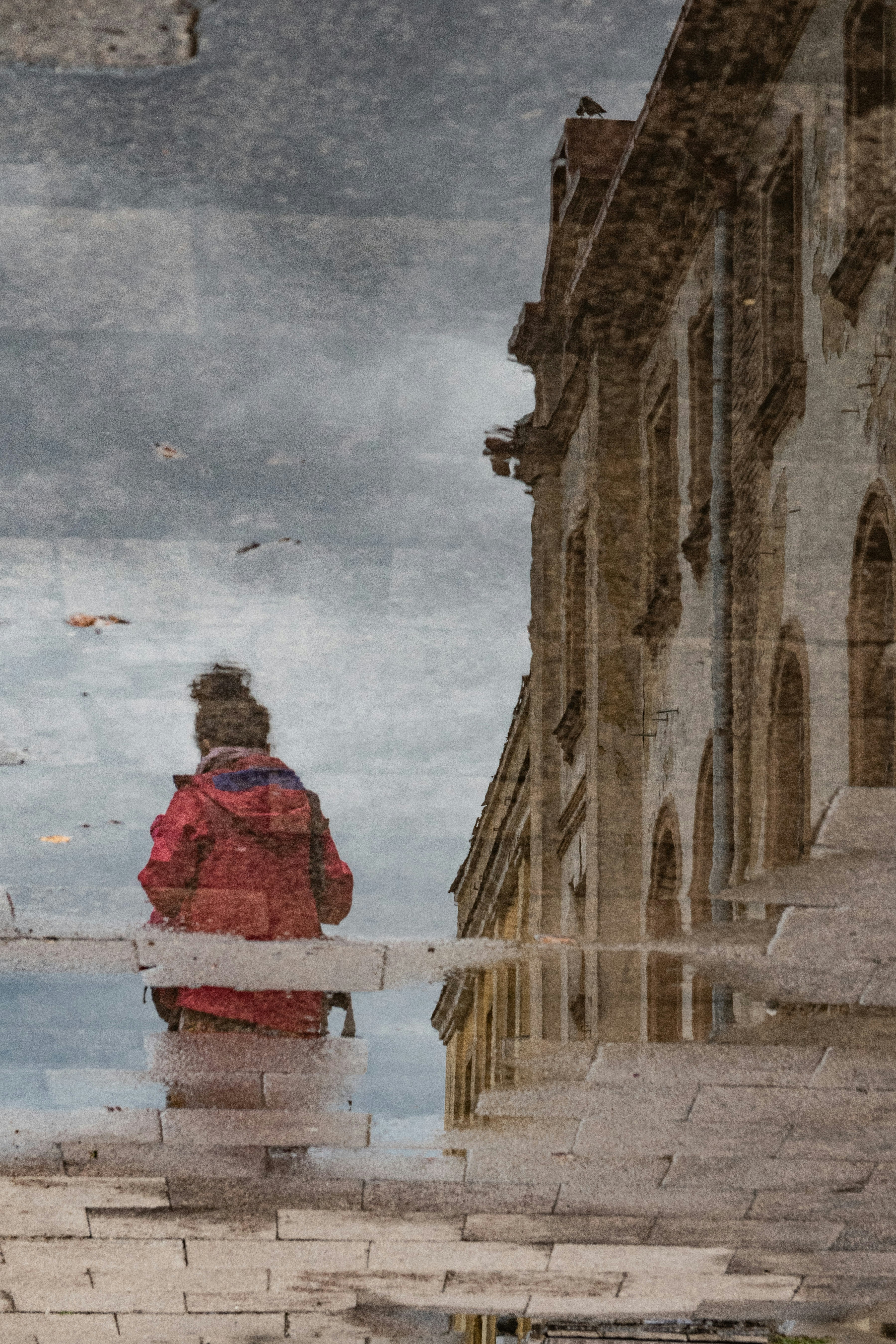 Reflection of a Stranger: A Red-Jacket Figure in a Weathered Urban Mirror