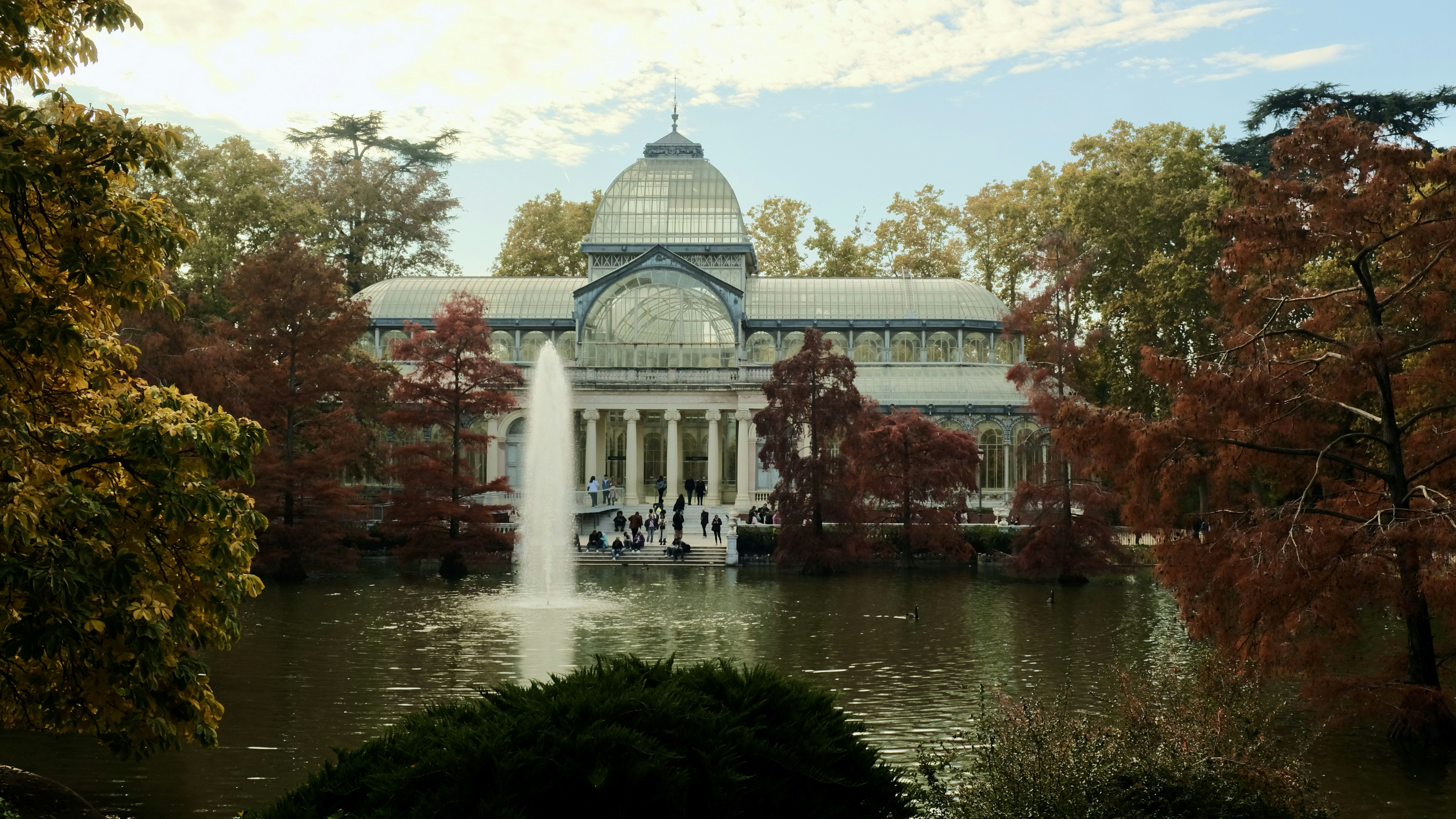 Glass Conservatory Rising Over a Tranquil Autumn Pond