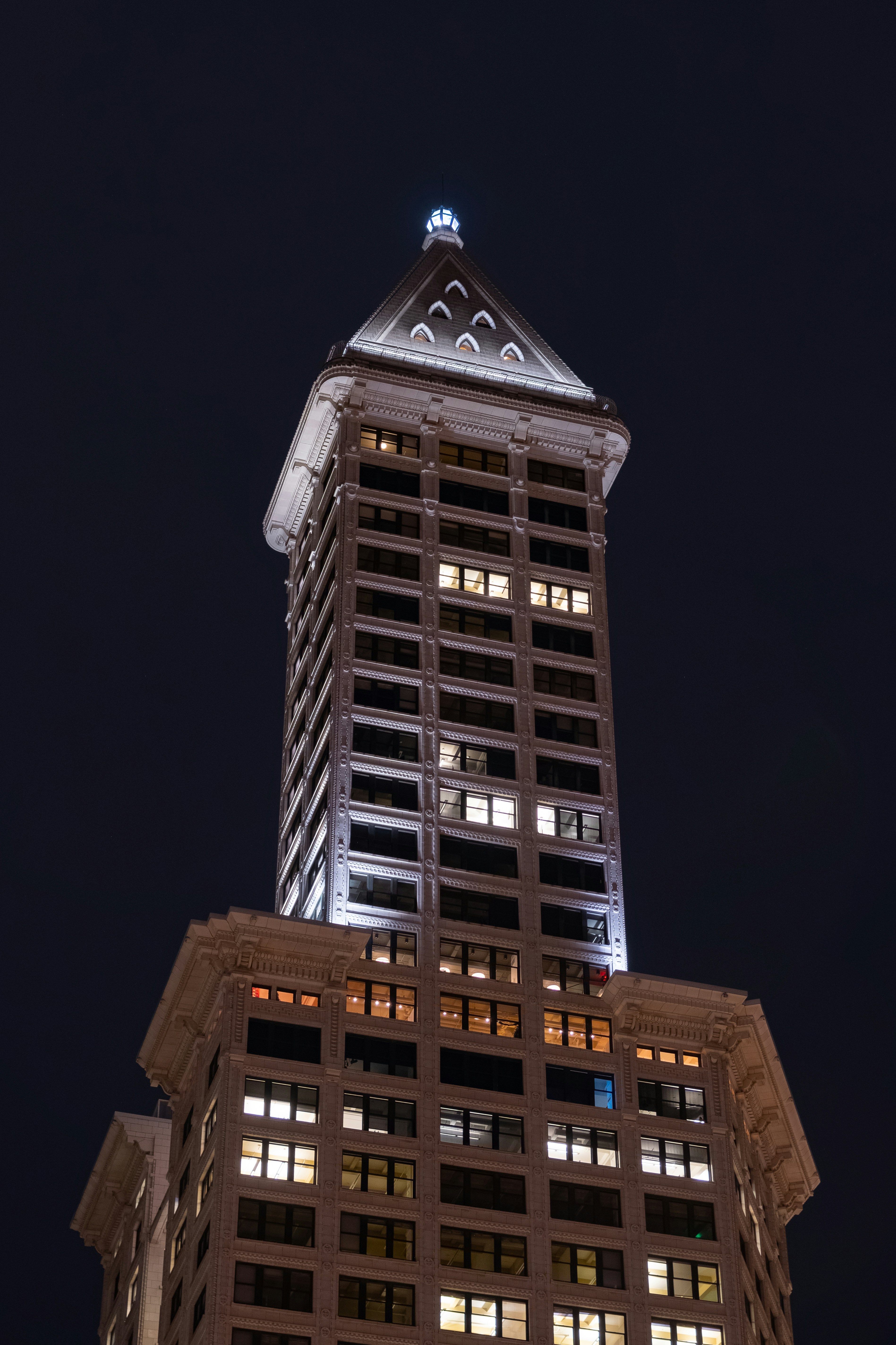 Apex of Night: Pyramid-Topped Tower Illuminated Against Darkness