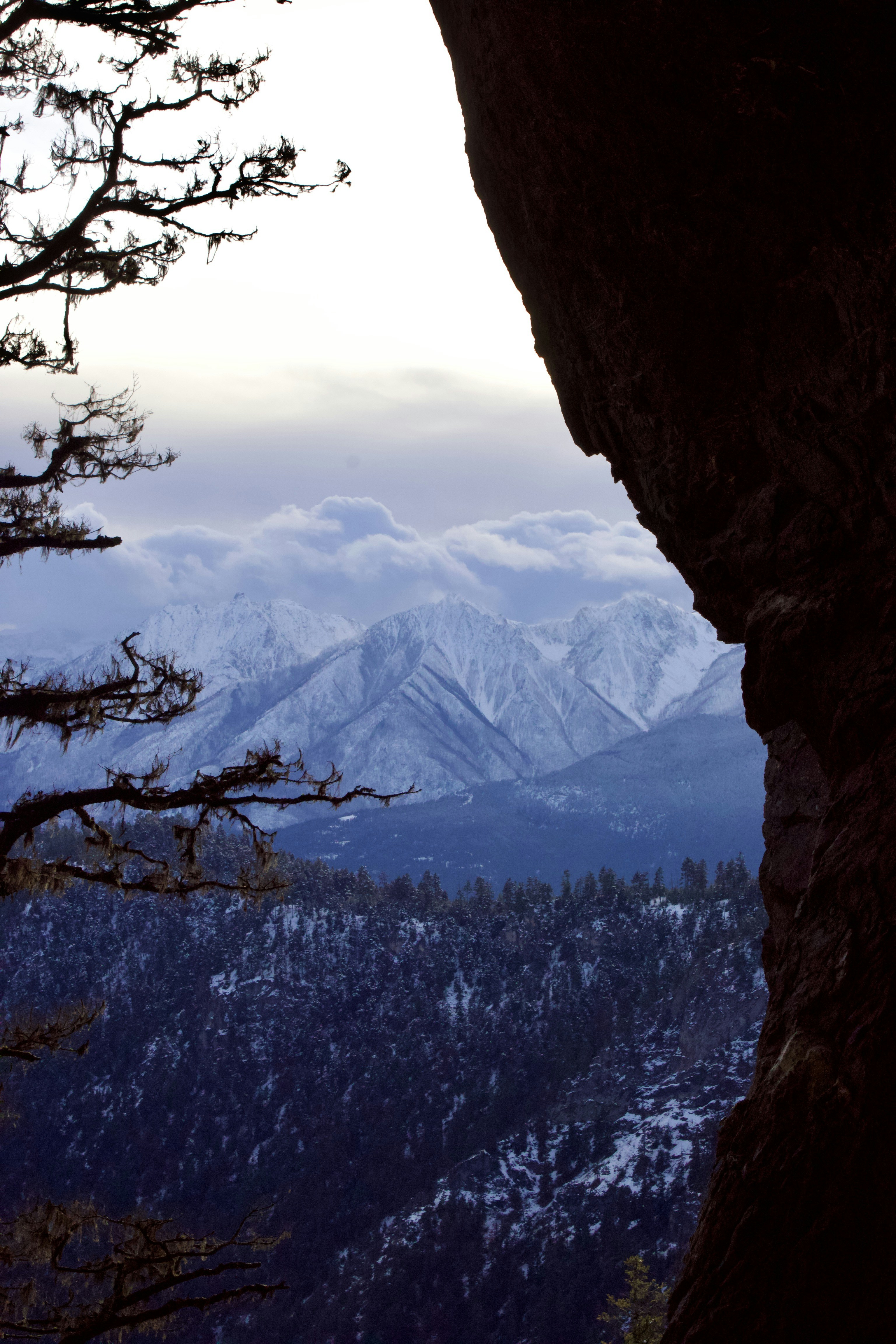 Framed Summit: Snow-Capped Peaks Through a Shadowed Cliff