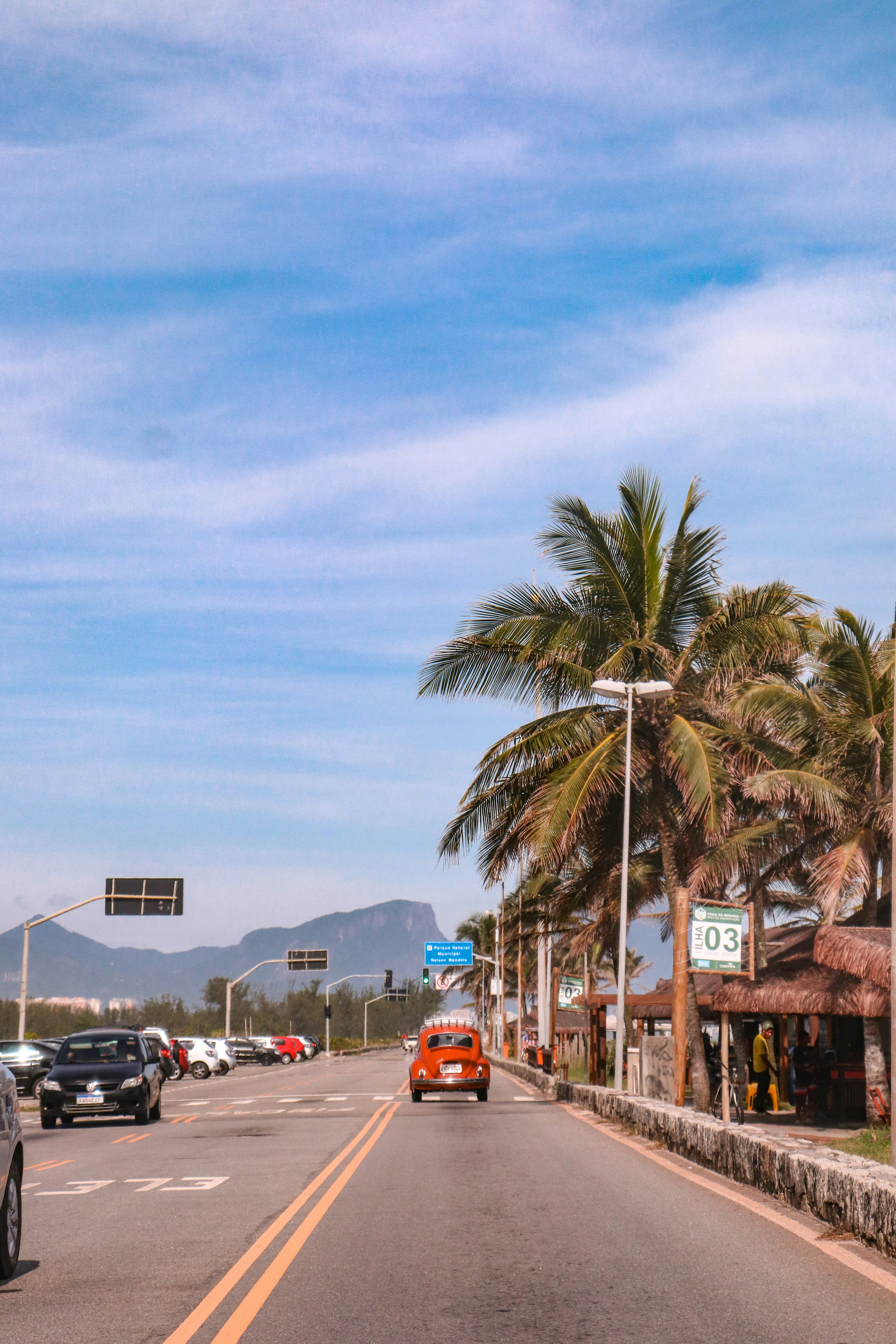 A red car driving down a street next to palm trees photo – Free Car ...