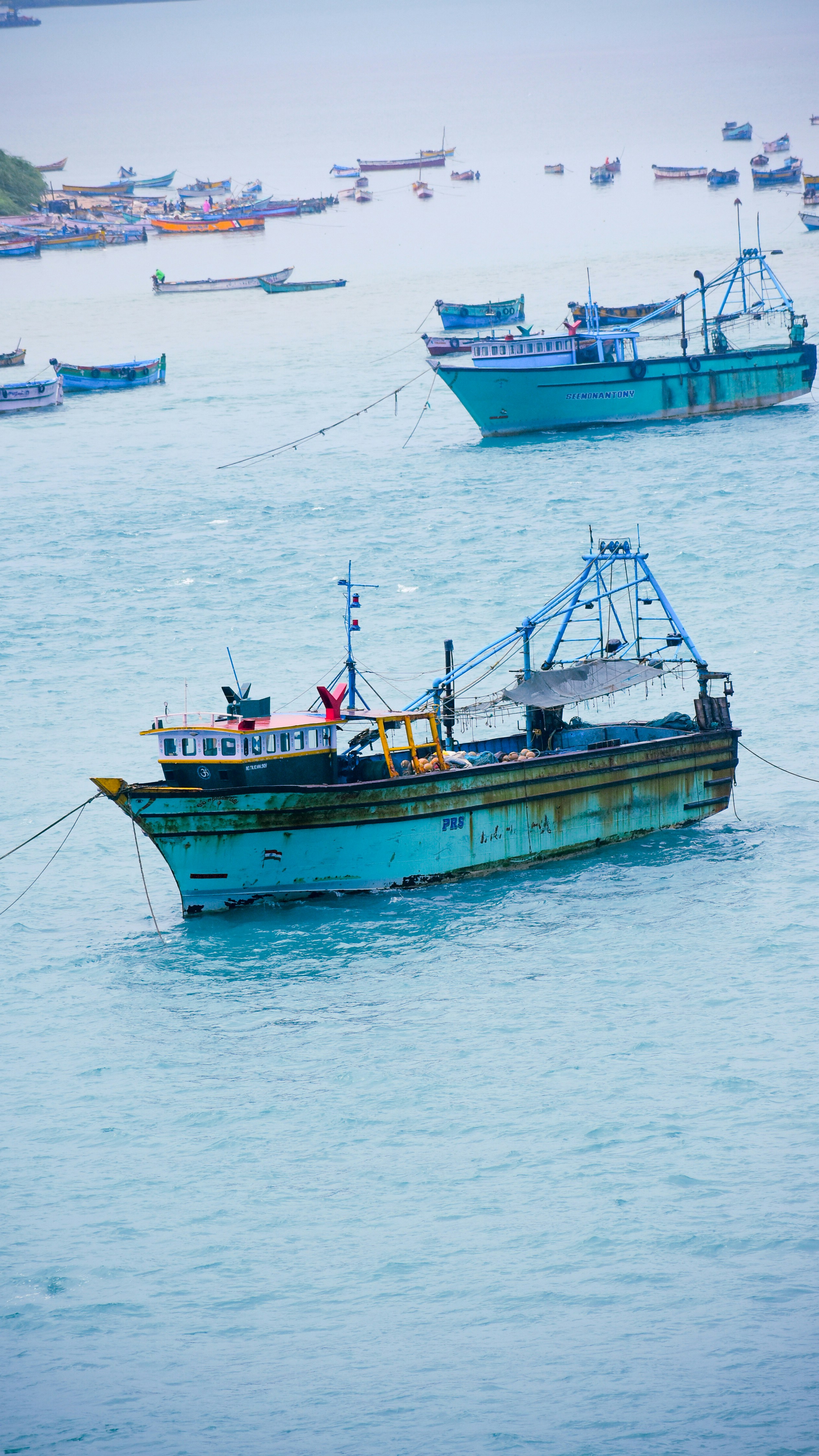 A weathered fishing boat navigates calm waters, surrounded by other vessels in the distance. The scene captures the essence of maritime life.