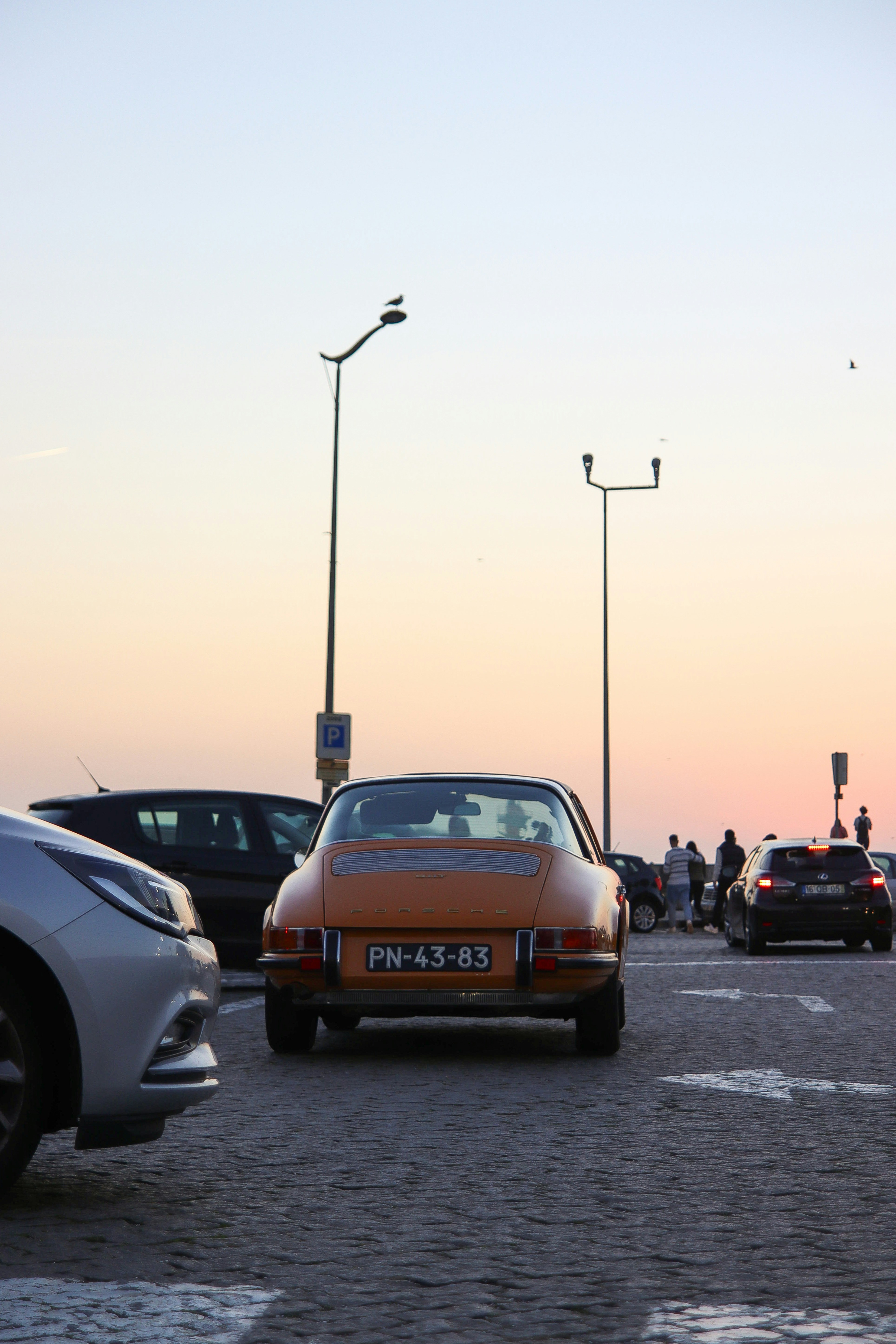 Dusk in the Cobblestones: An Orange Classic Porsche at the Seaside Parking Lot