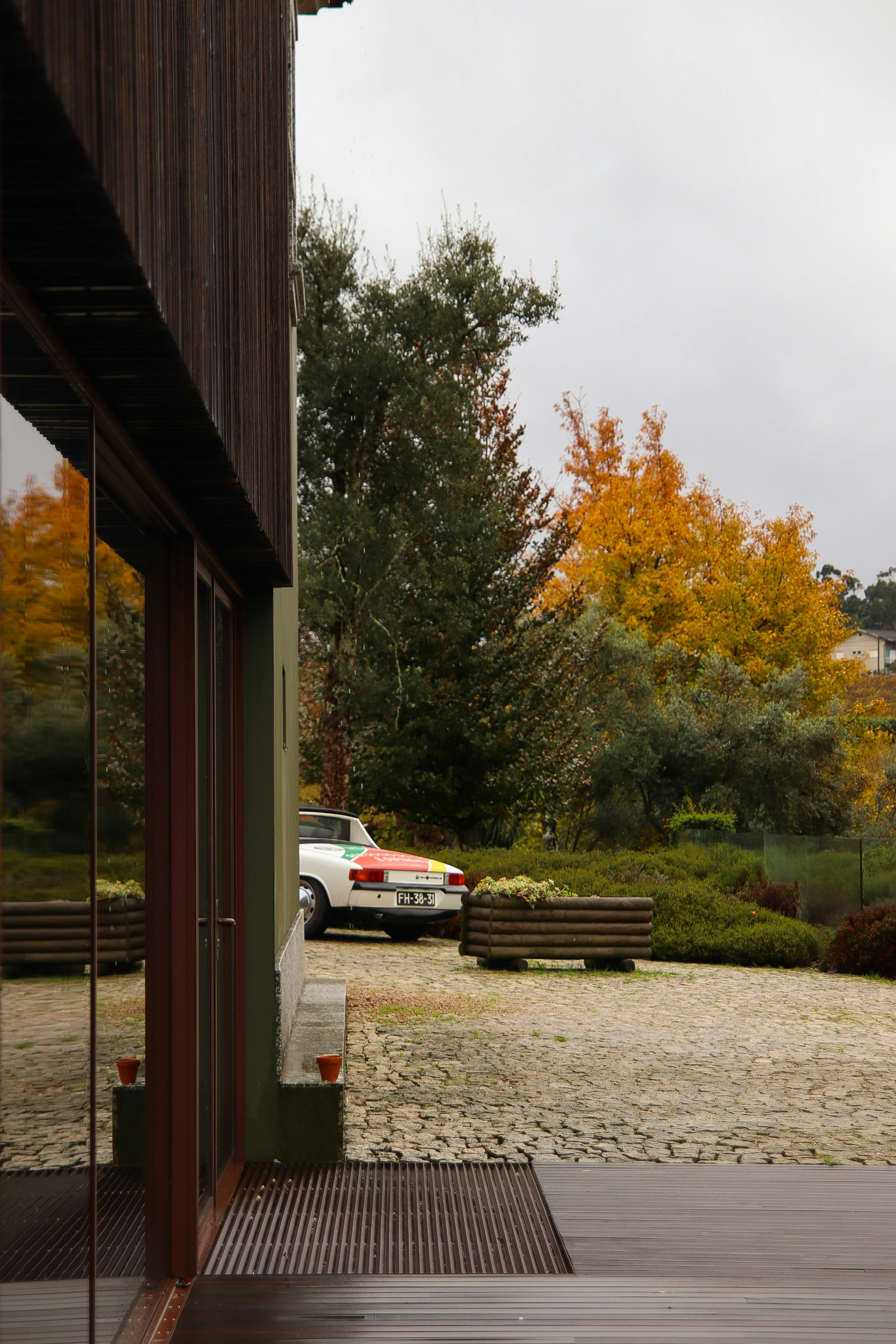 Autumn Courtyard glimpse: parked car beyond the glass and timber