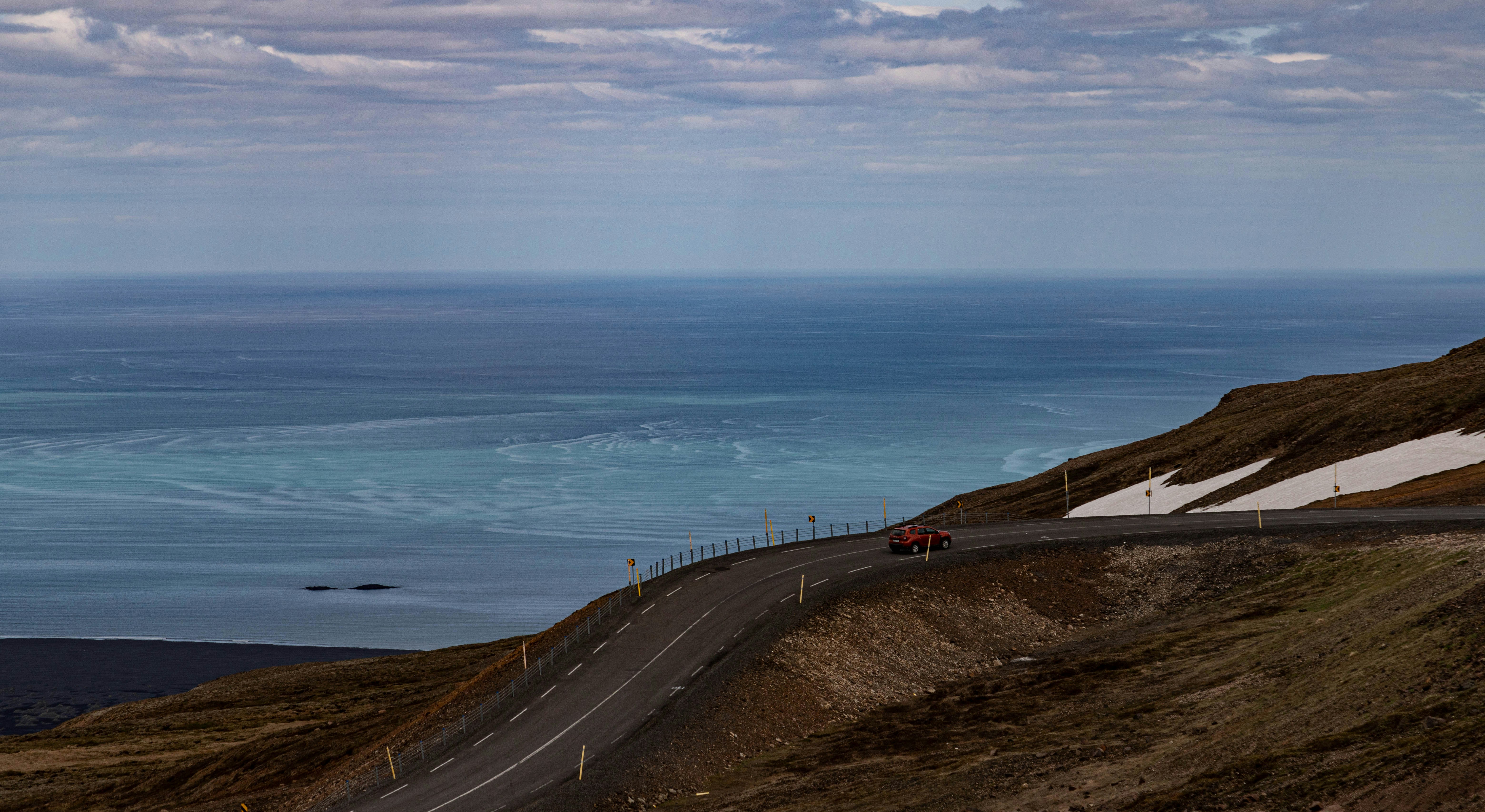 a car driving down a road next to the ocean