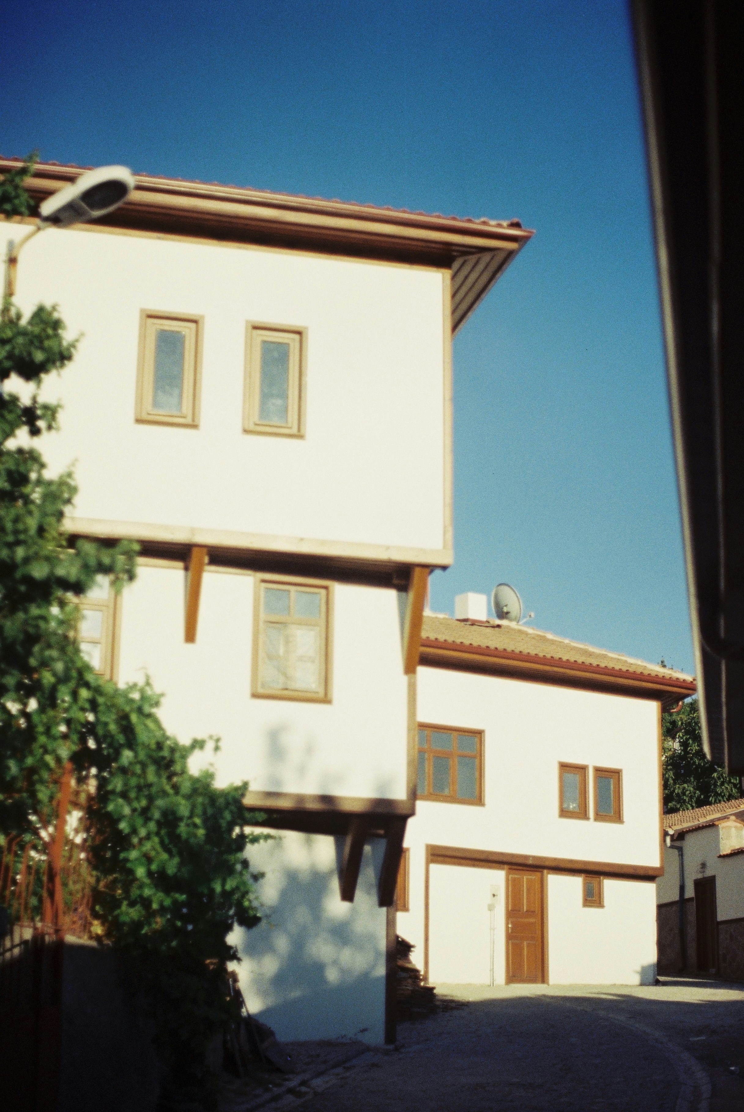 Cantilevered Quiet: White Facade on a Sunlit Street