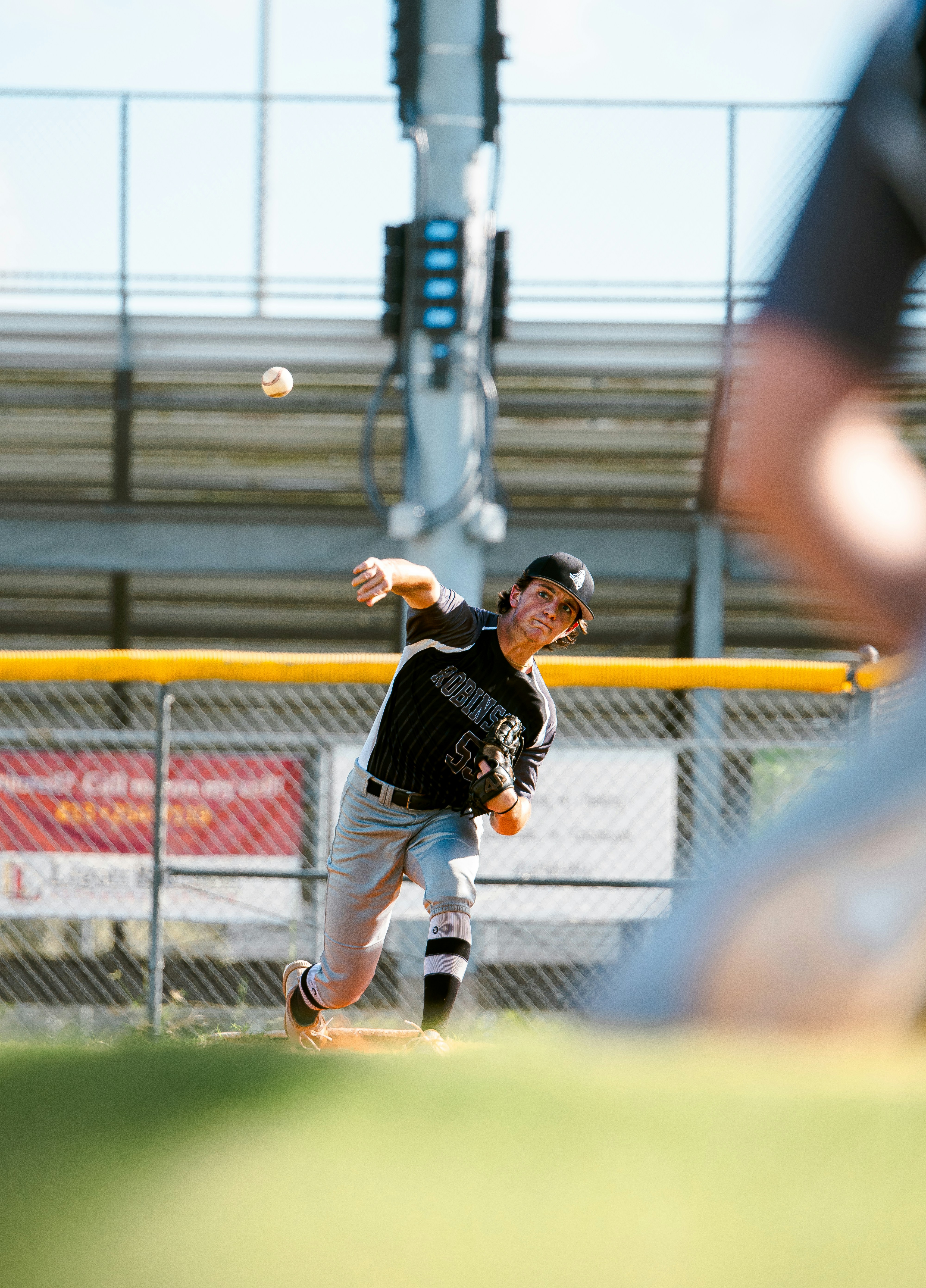 A young baseball player in mid-throw, showcasing athleticism on the field during a game. The scene captures the intensity and focus of the sport.
