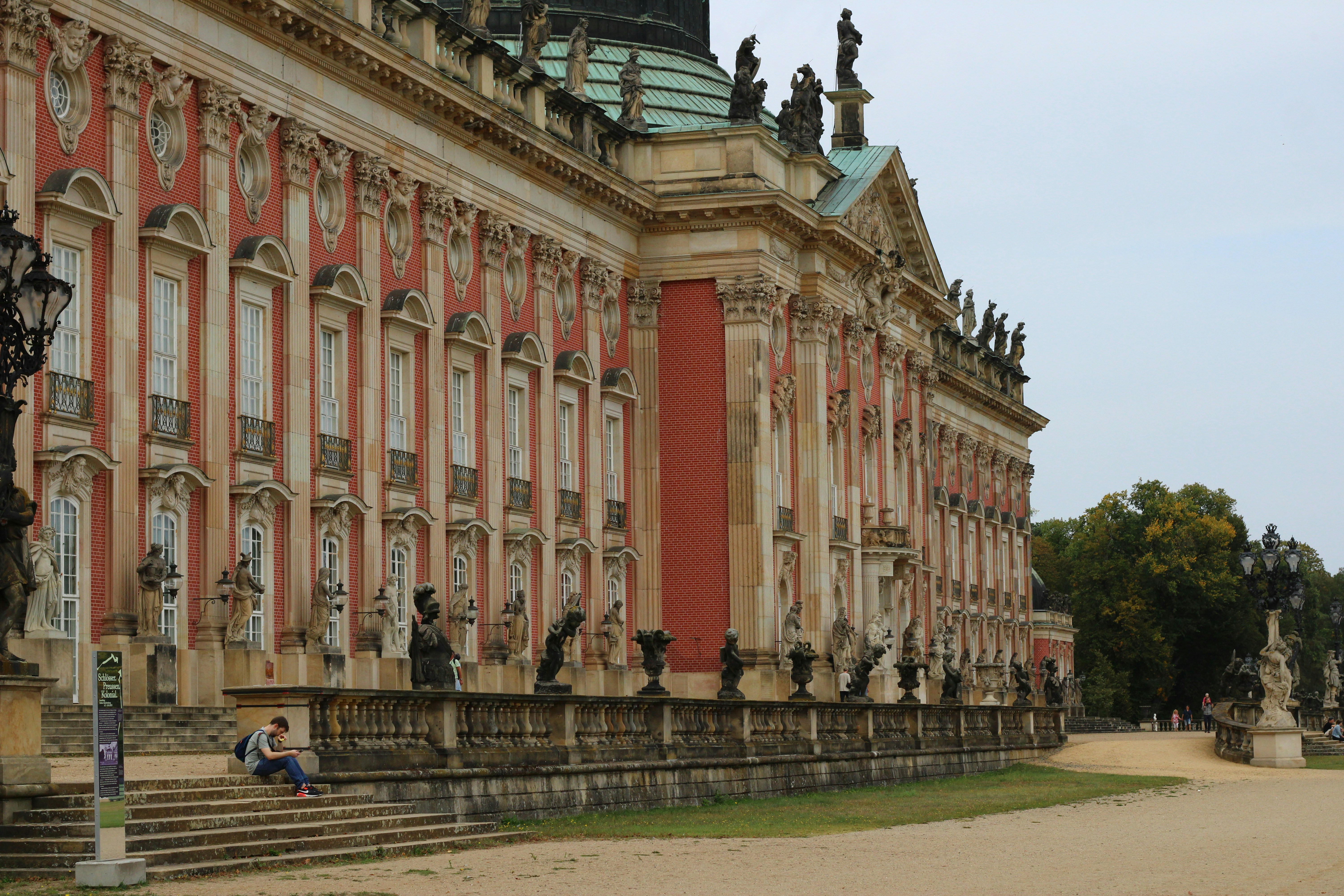 Foto Una persona sentada en un banco frente a un edificio – Imagen Potsdam gratis en Unsplash
