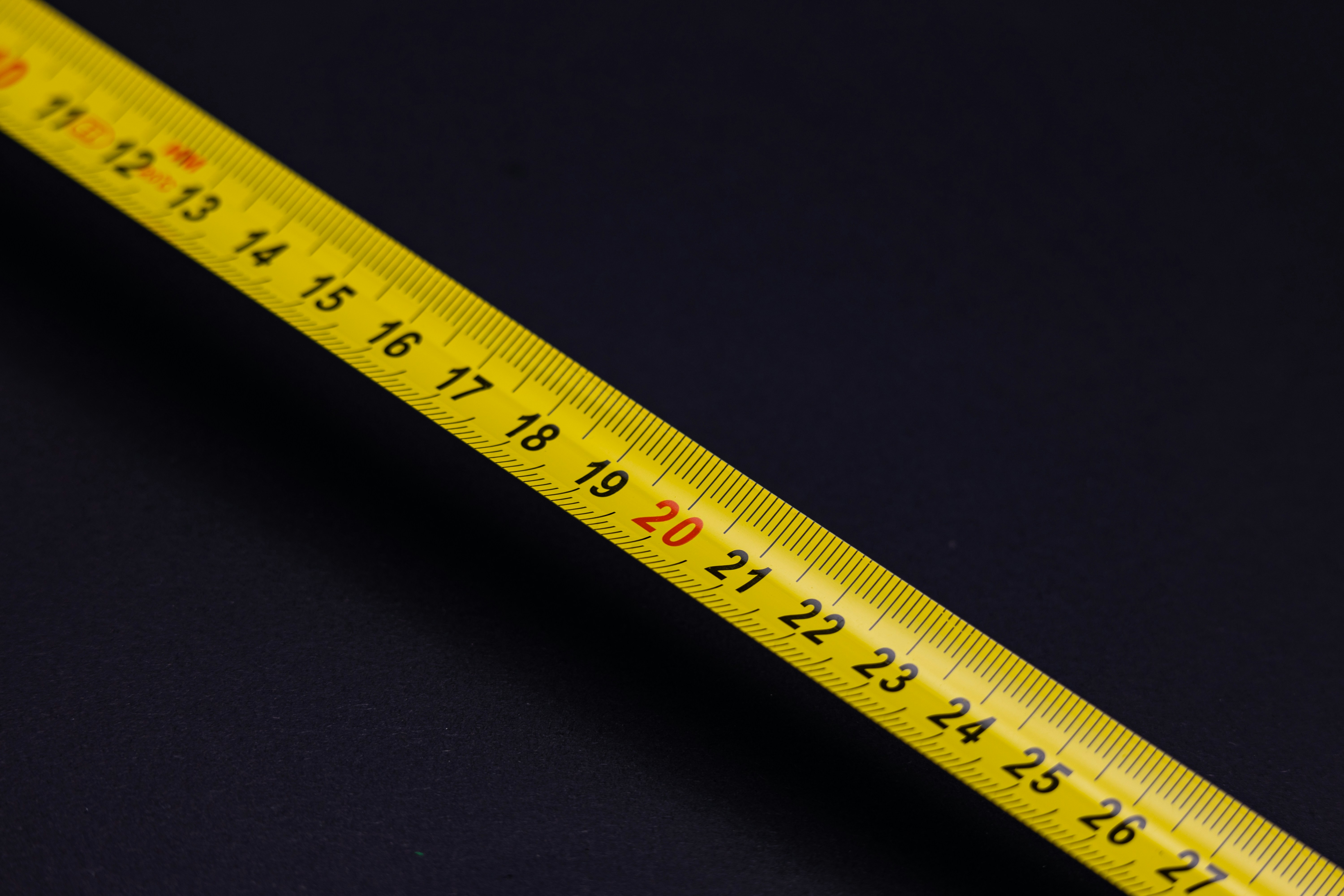 A yellow measuring tape on a black surface photo – Free Plot Image on ...