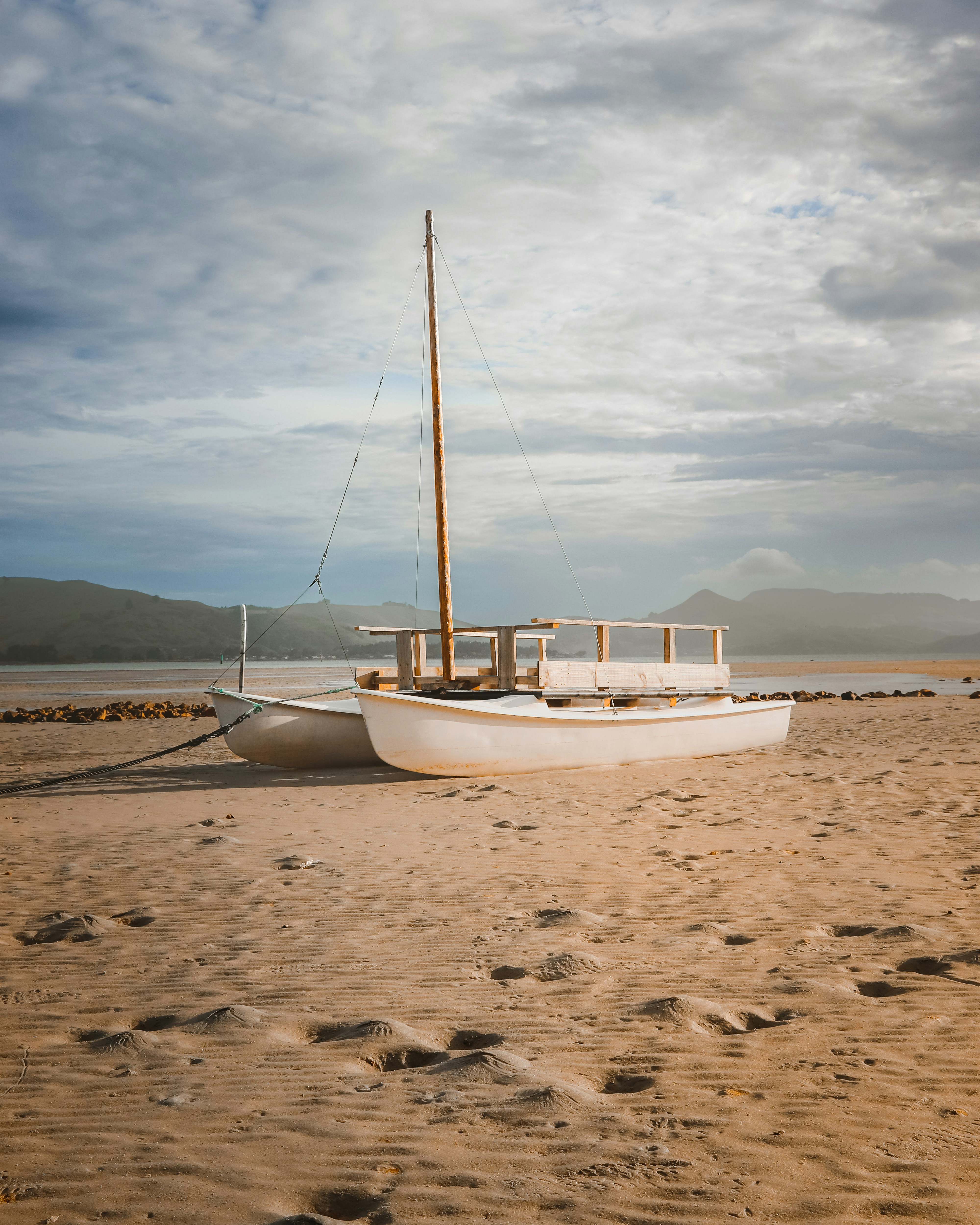 A sailboat on the beach with footprints in the sand photo – Free Boat ...