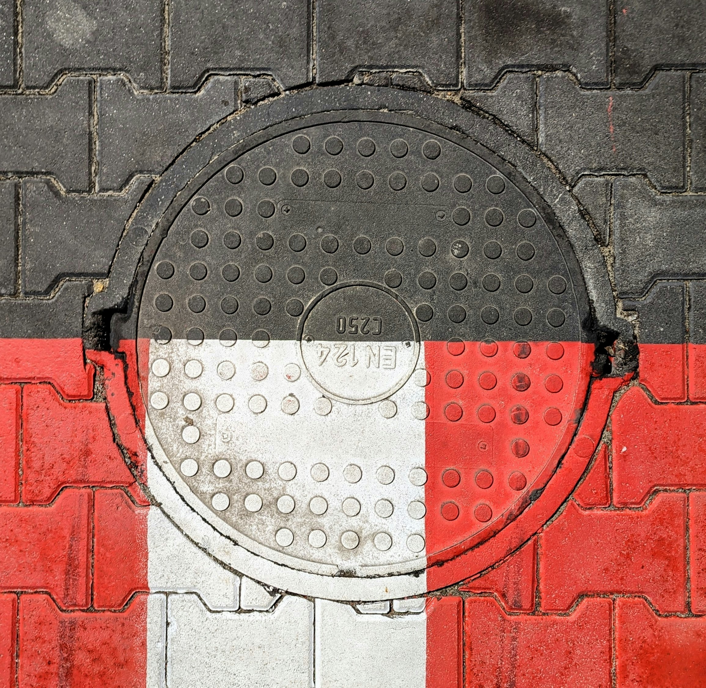 Red, White, and Steel: A Circular Manhole Grounded in Street Color
