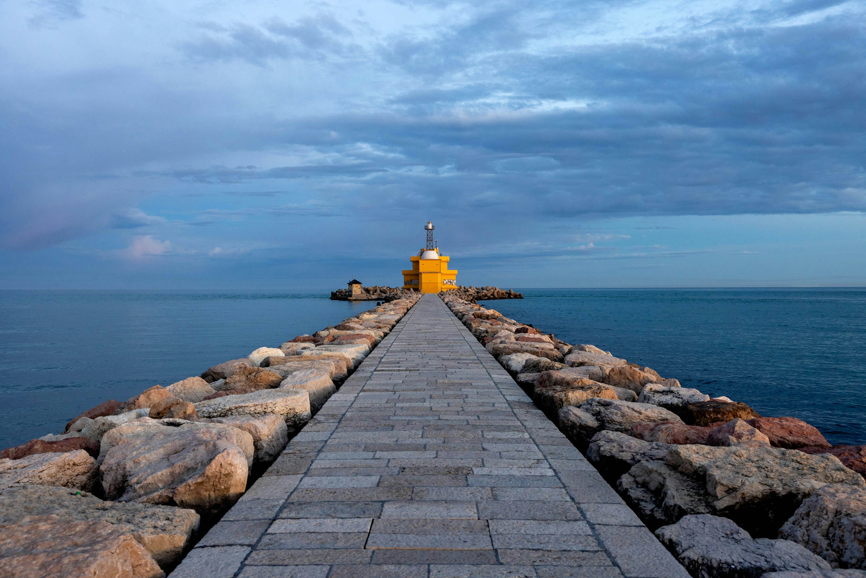 A yellow lighthouse sitting on top of a pier next to the ocean photo ...