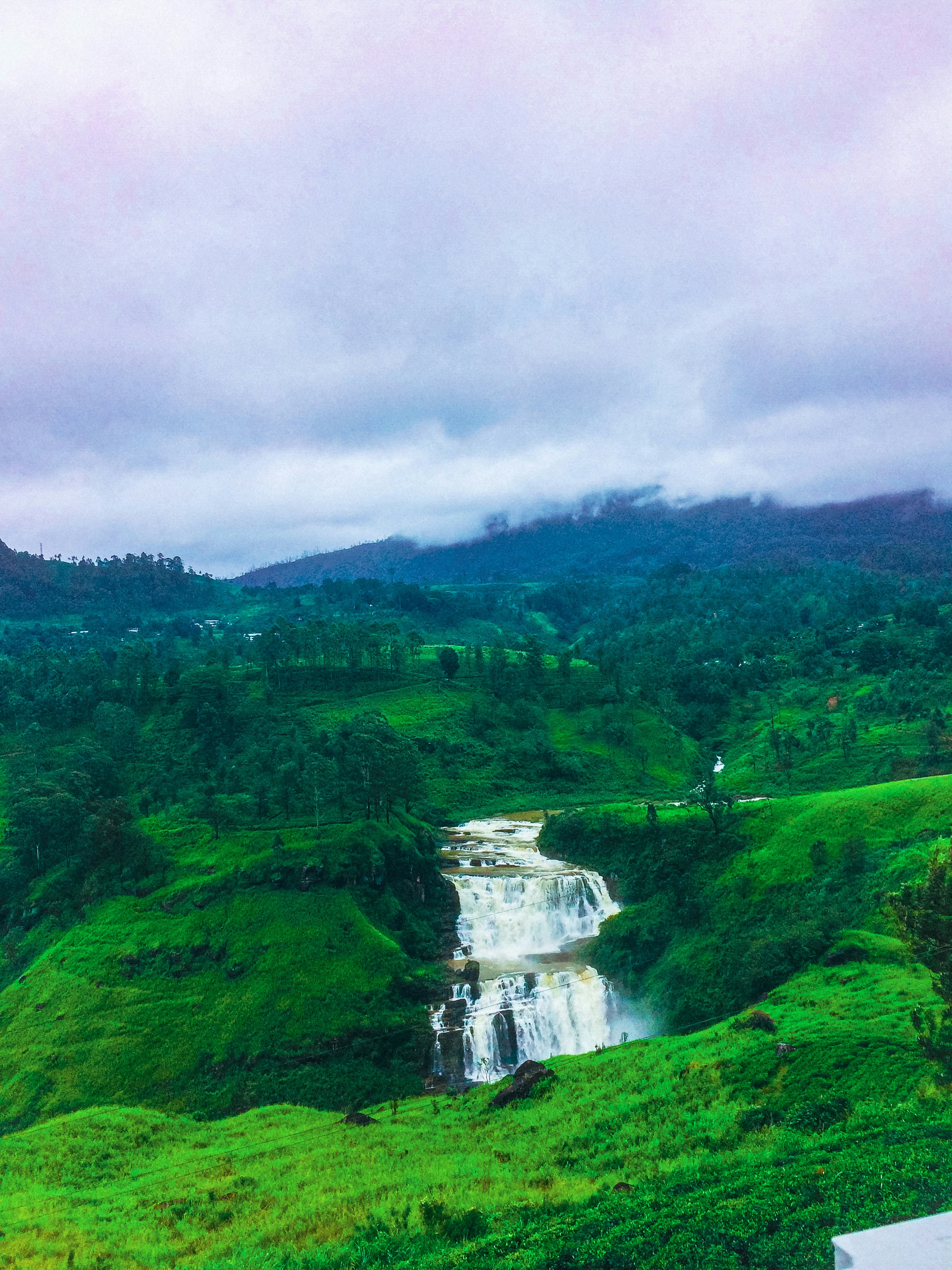 Emerald Highlands Cascade Under a Veiled Sky
