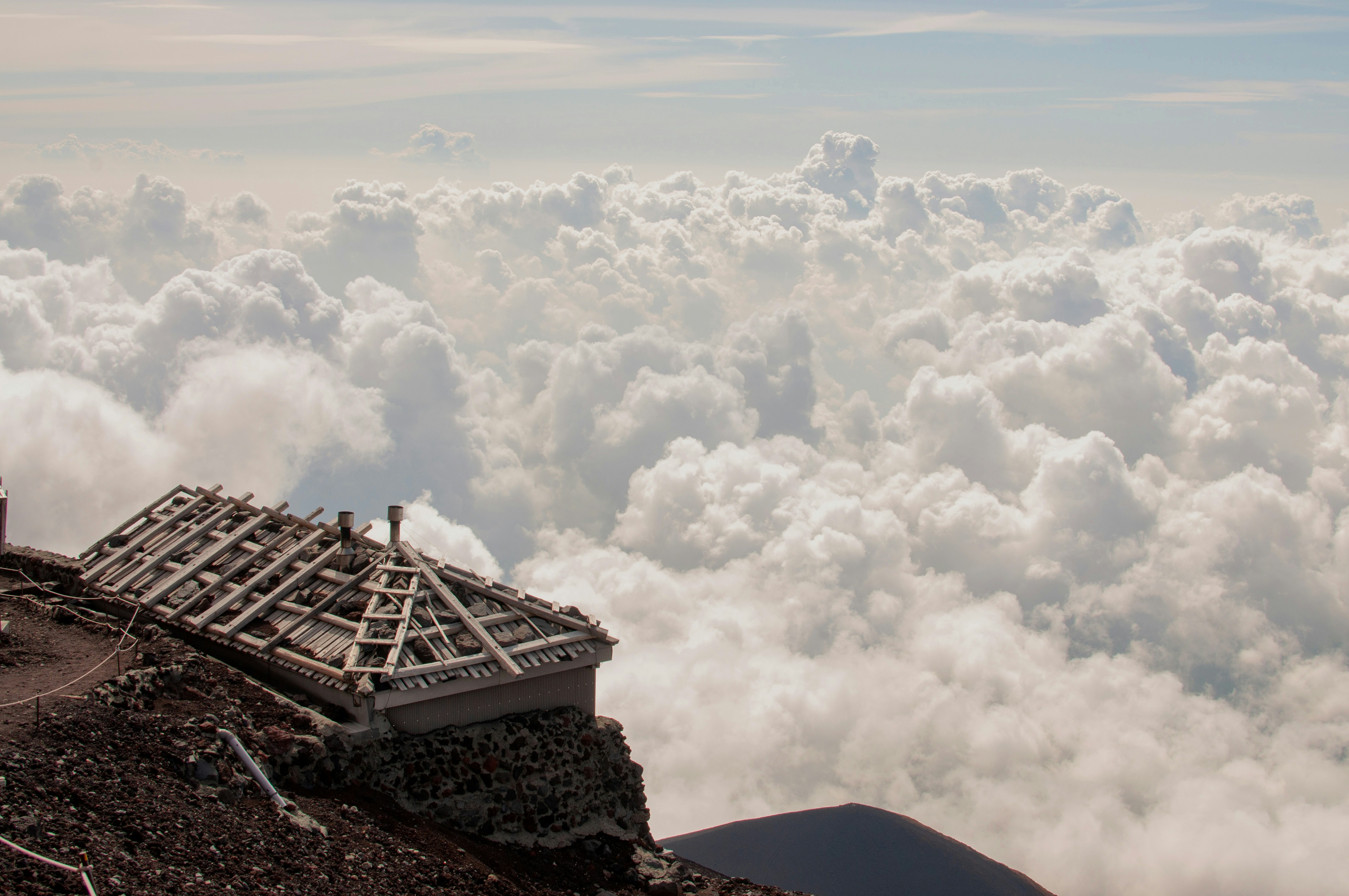 Weathered structure perched on a mountain slope, surrounded by a sea of clouds.