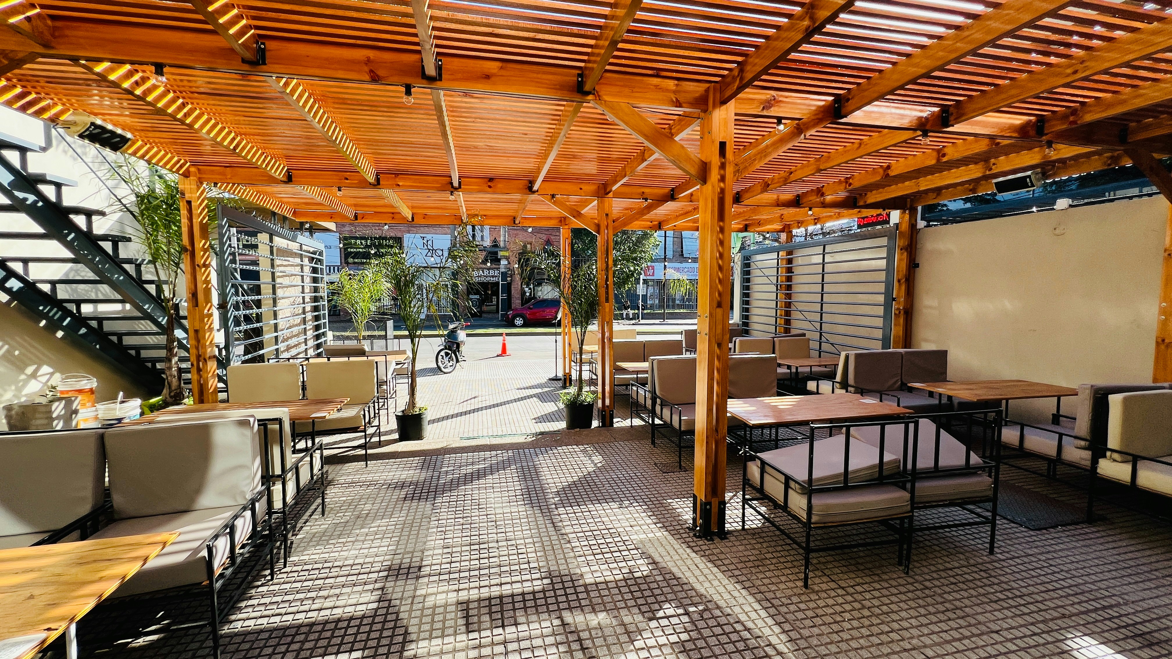 A patio with tables and chairs under a wooden roof photo – Free ...