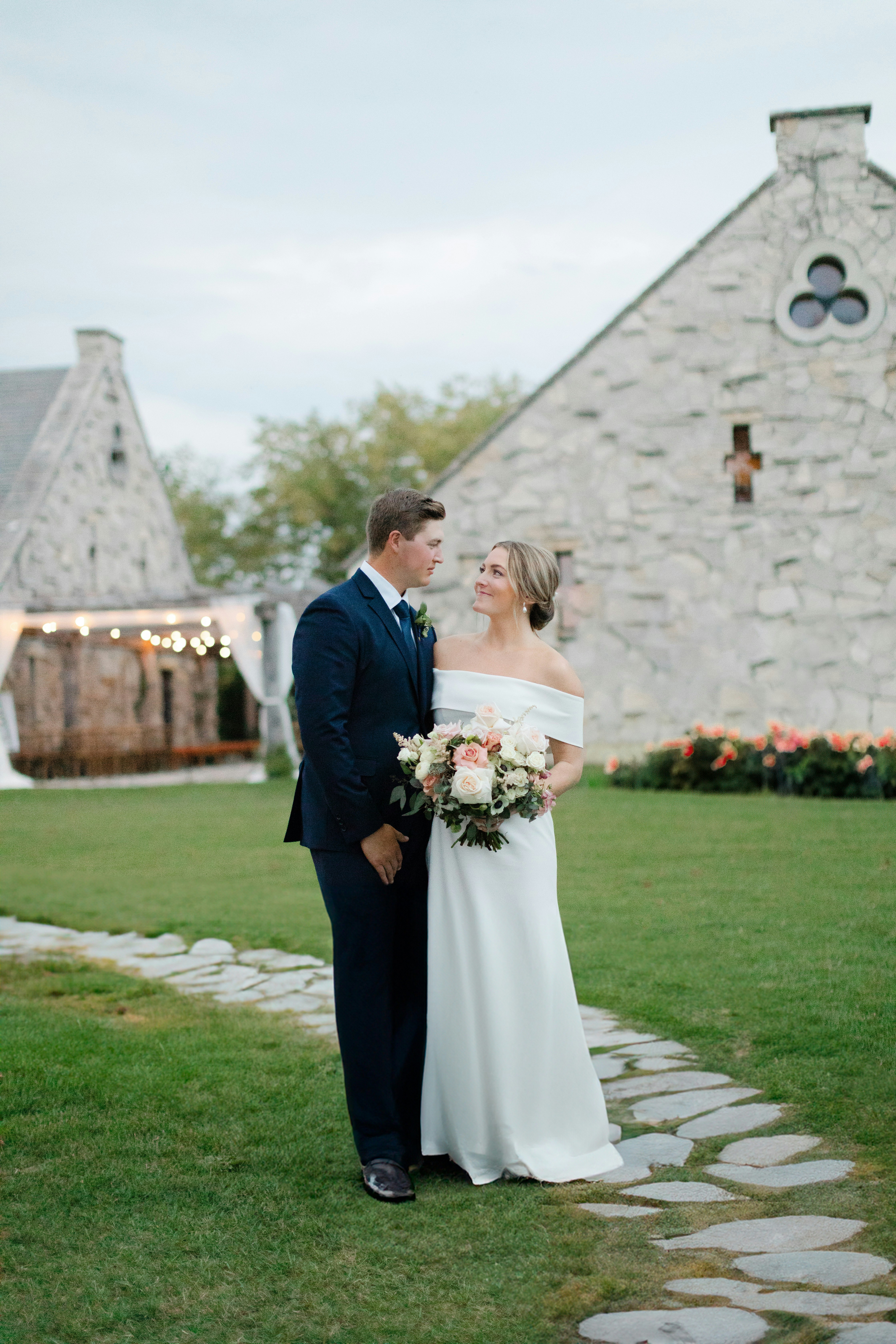 A bride and groom standing in front of a stone building photo – Free ...