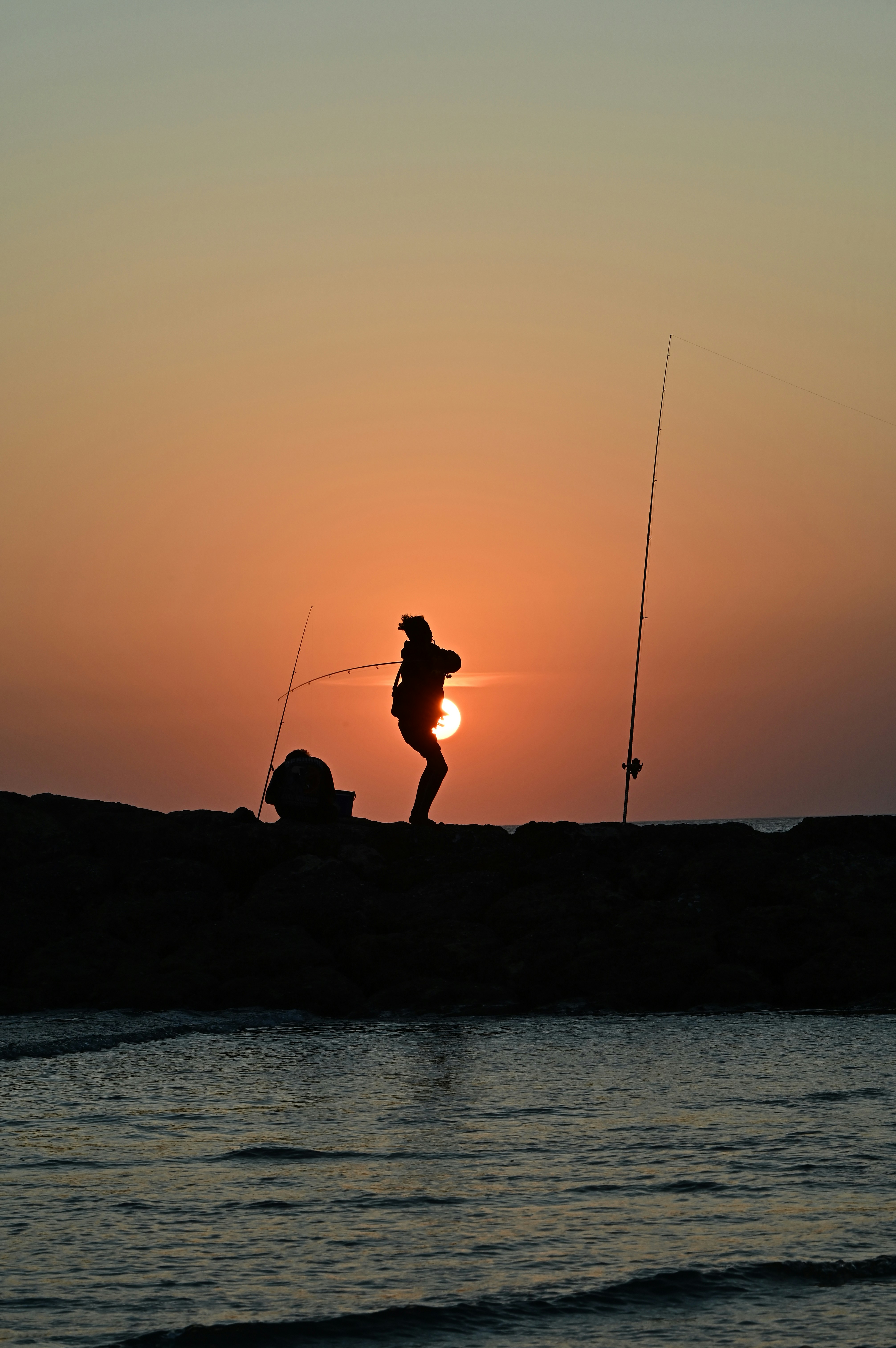 Sunset Silhouette: A Lone Angler Casting Against a Fiery Horizon
